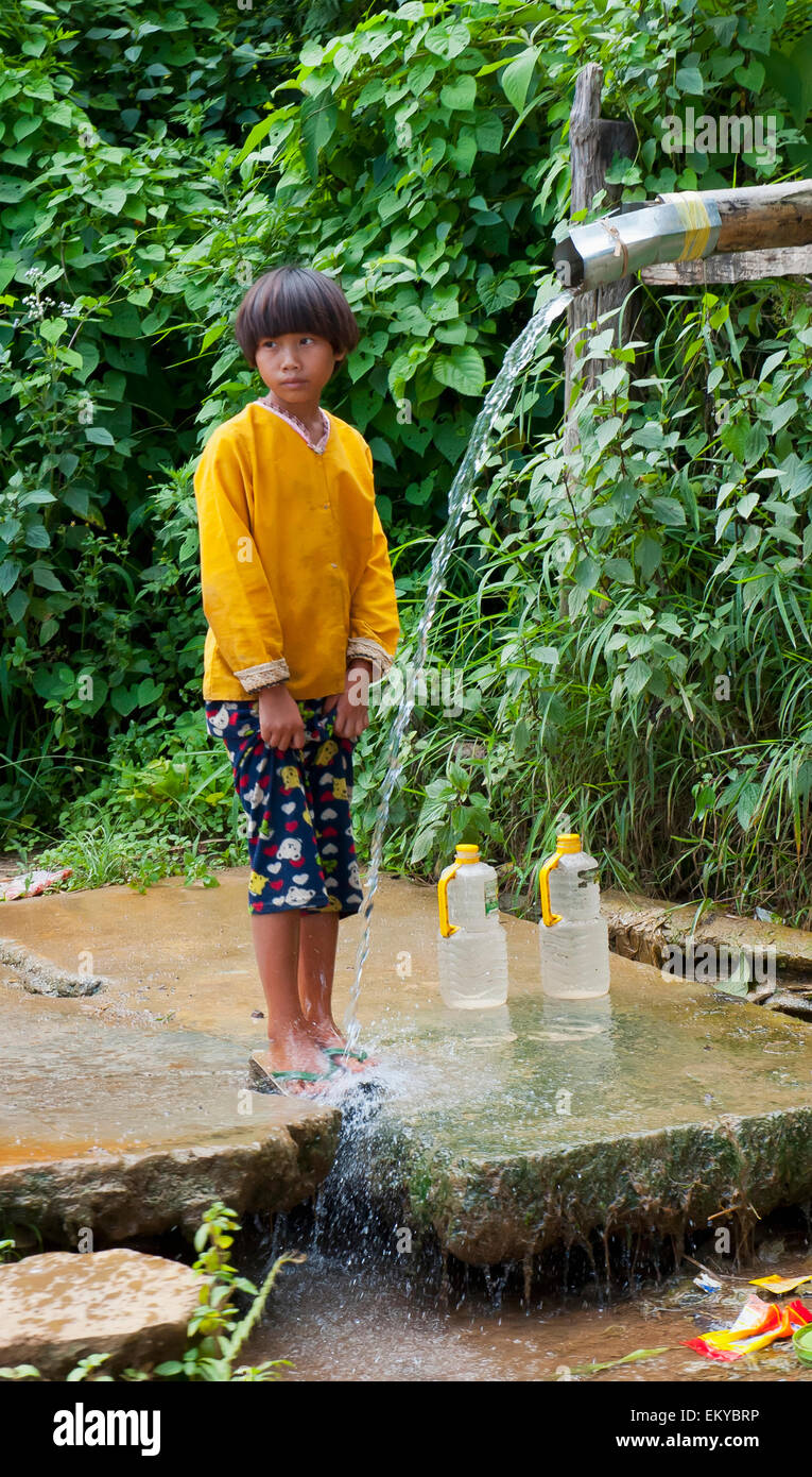 Burma, Shan State, A boy stands beside water pouring out of a water ...