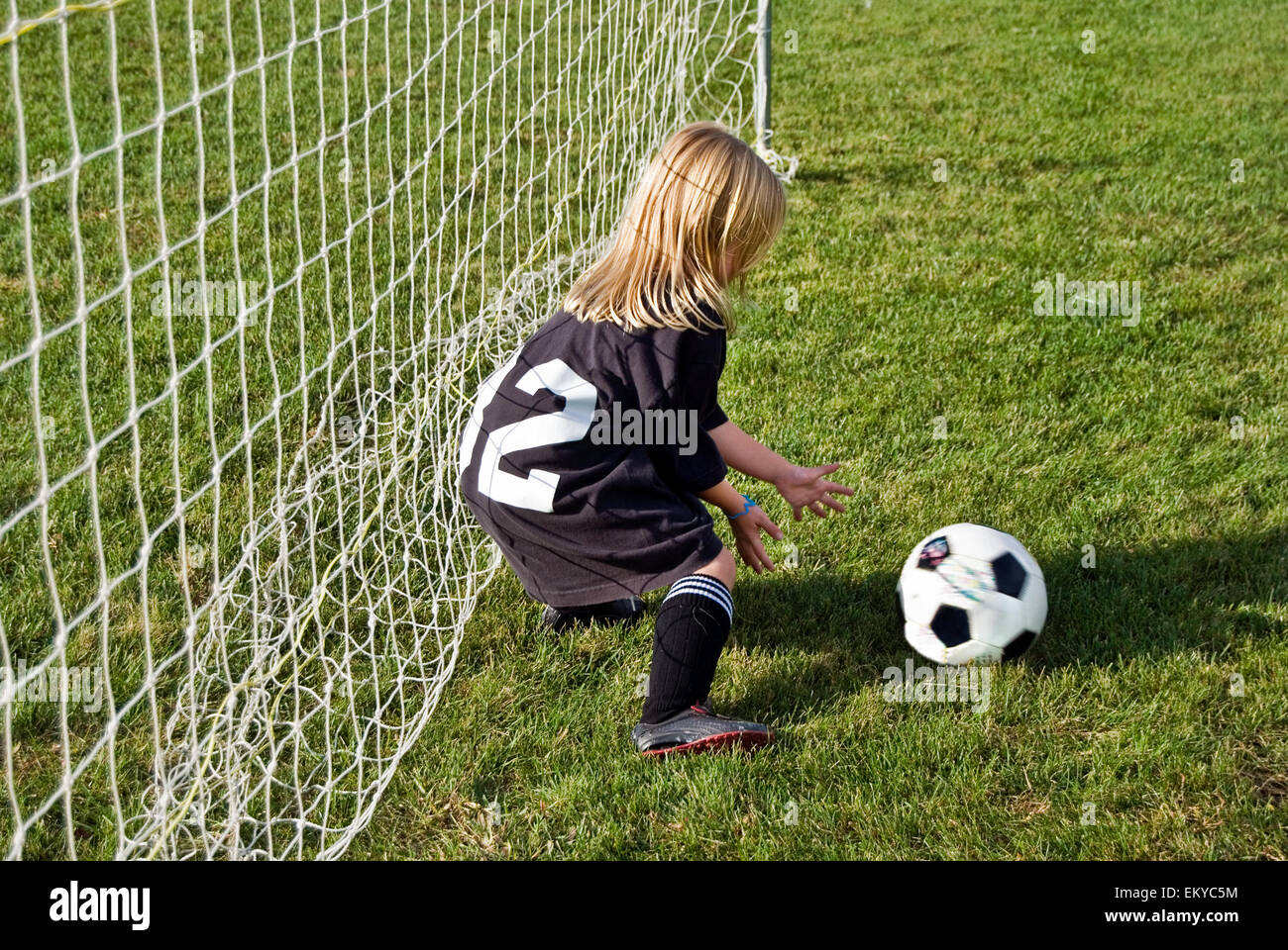 Little girl playing goalie in soccer by the net Stock Photo - Alamy