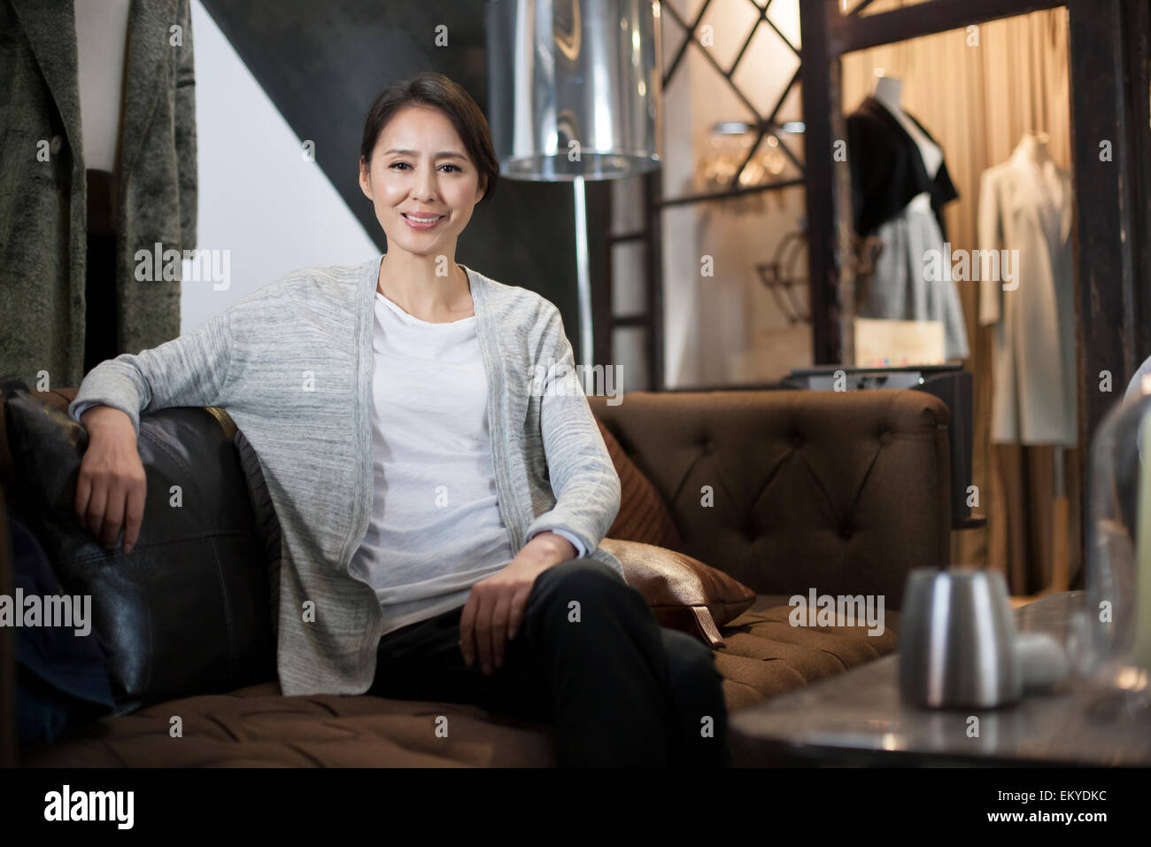 Clothing store owner sitting on sofa Stock Photo - Alamy