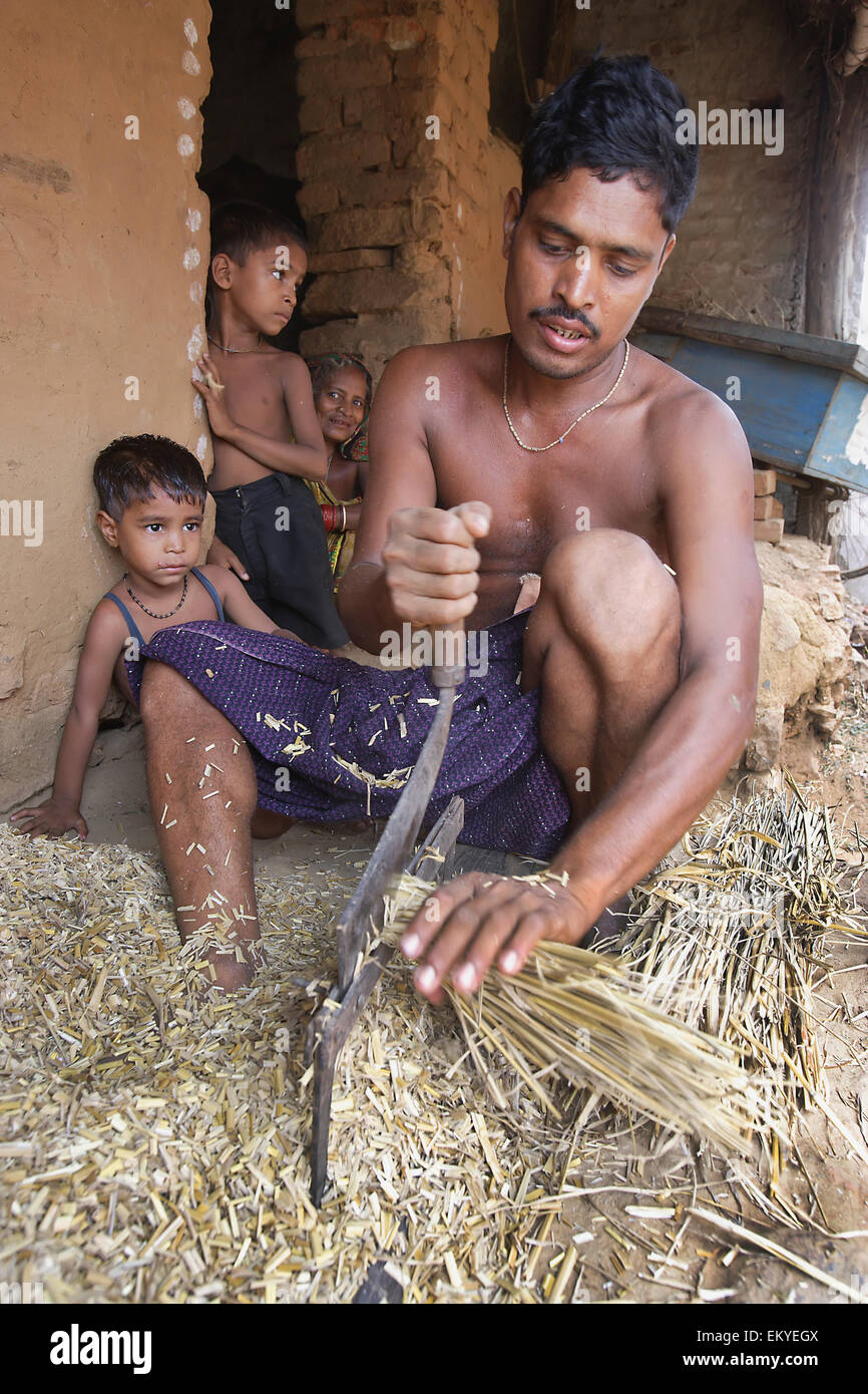 A father chops animal feed as daughter watches; Ratapata Village ...