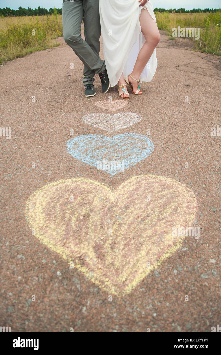 Heart symbols shaped with crayons on ground and two people in love ...