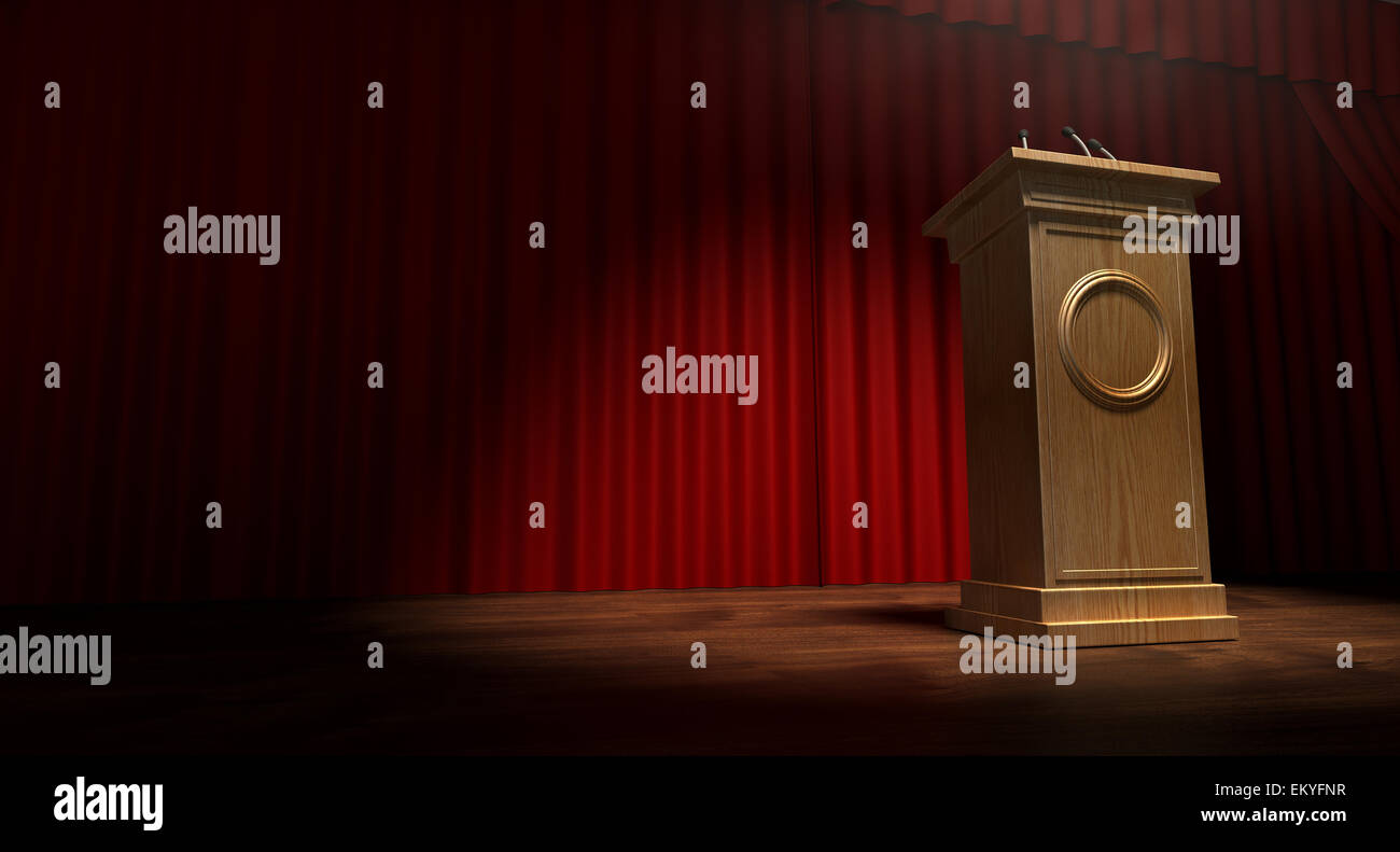 A regular theater stage with closed red curtains and a wooden debate ...