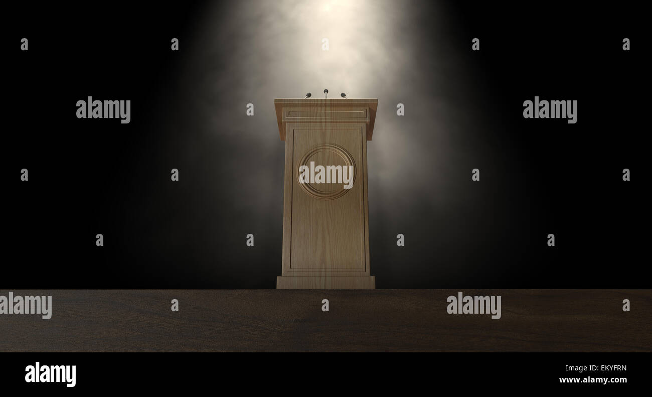 A wooden speech podium with three small microphones attached on a dark ...