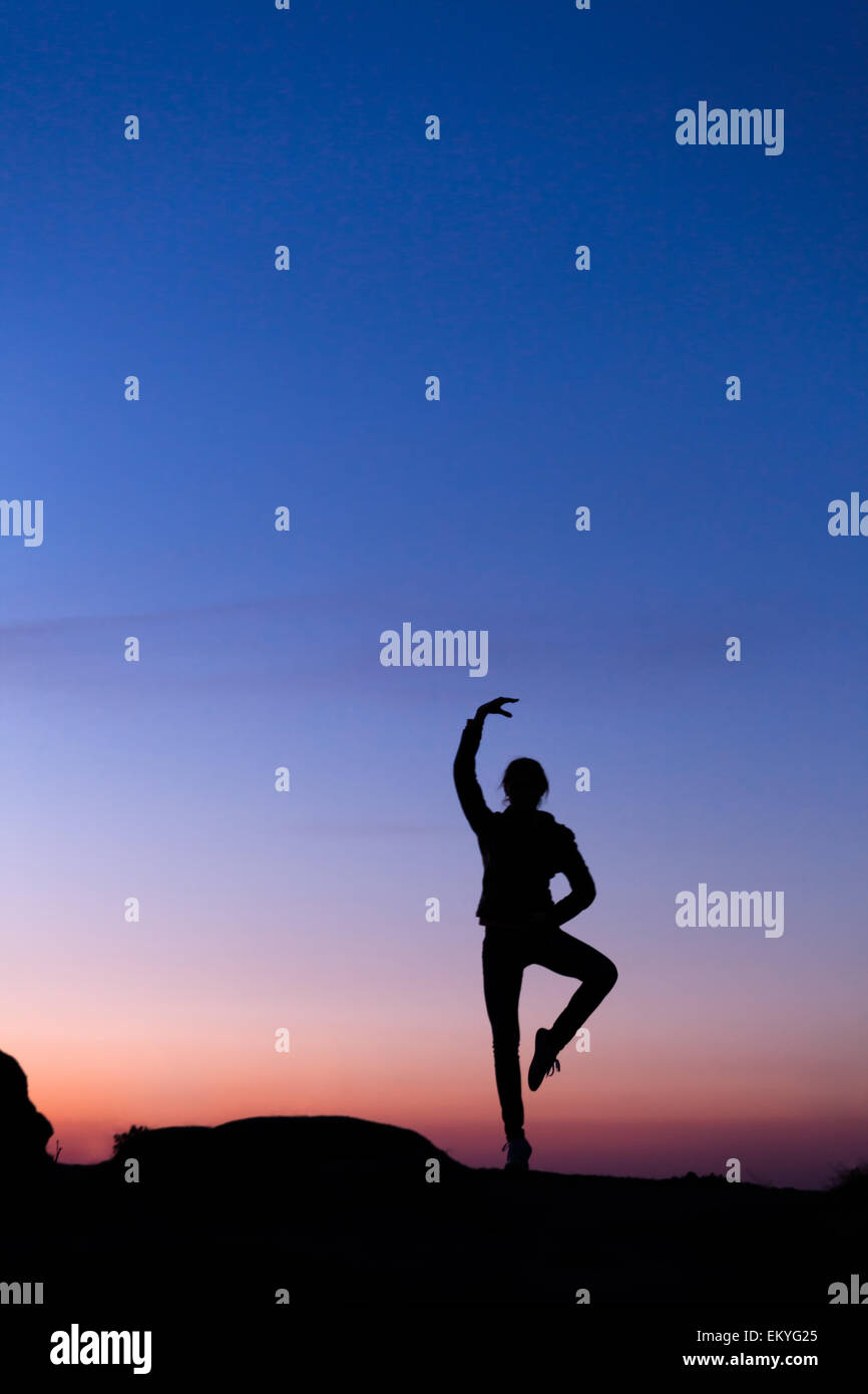 Silhouette of happy young woman with arms raised up against beautiful ...