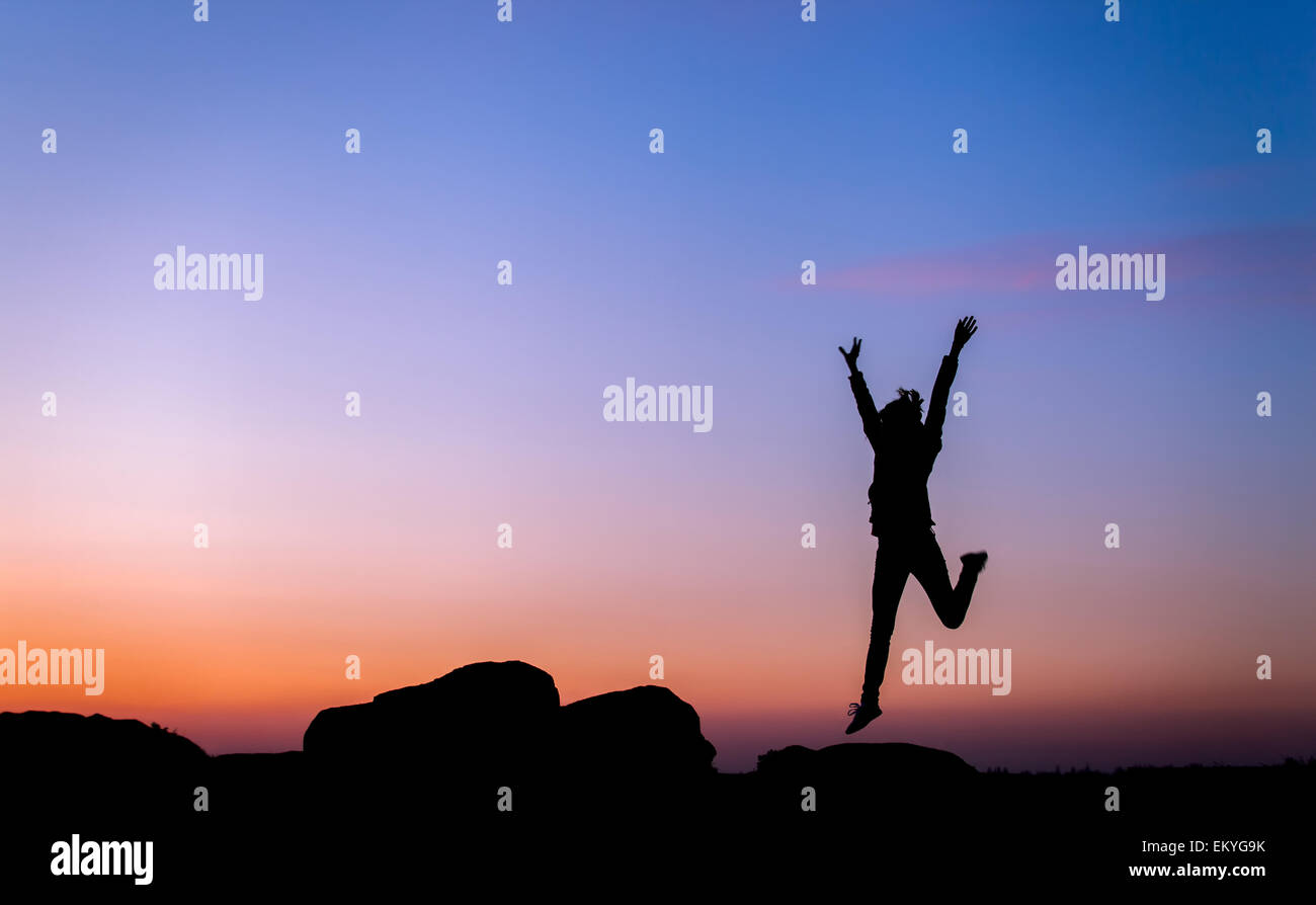 Silhouette of happy young woman with arms raised up against beautiful ...