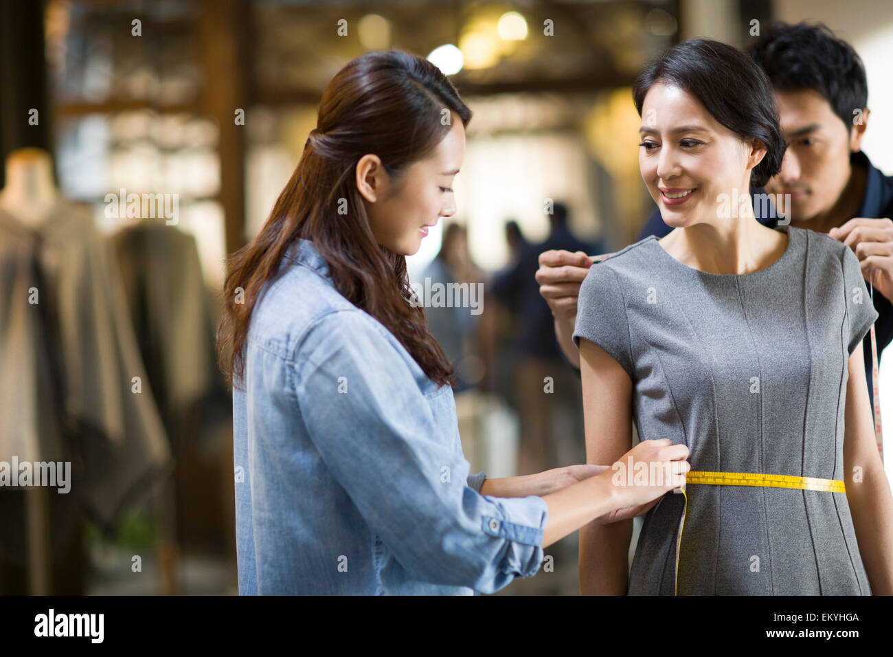 Fashion designers taking measurement of customer Stock Photo - Alamy