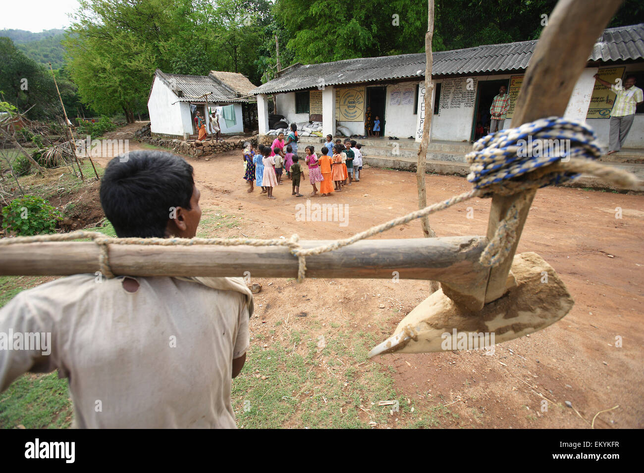 A farmer carrying his plough walks past the children gathered outside ...