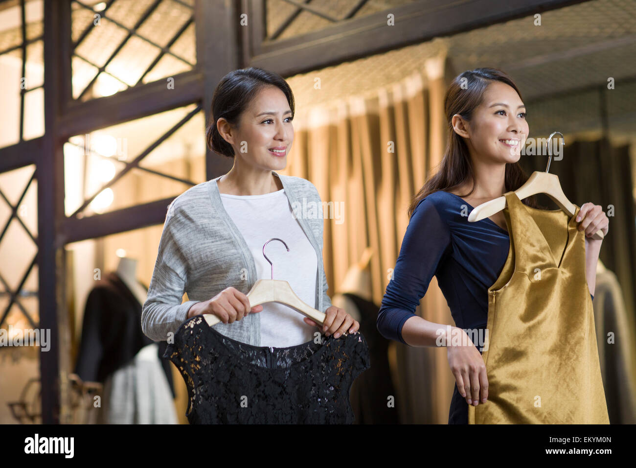 Clothing store owner helping customer with choosing dress Stock Photo ...