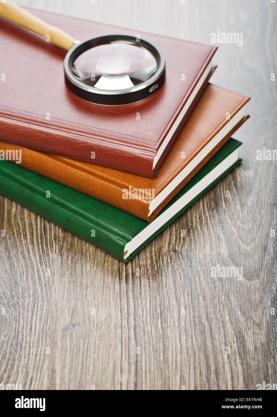 three notebooks and magnifier Stock Photo - Alamy