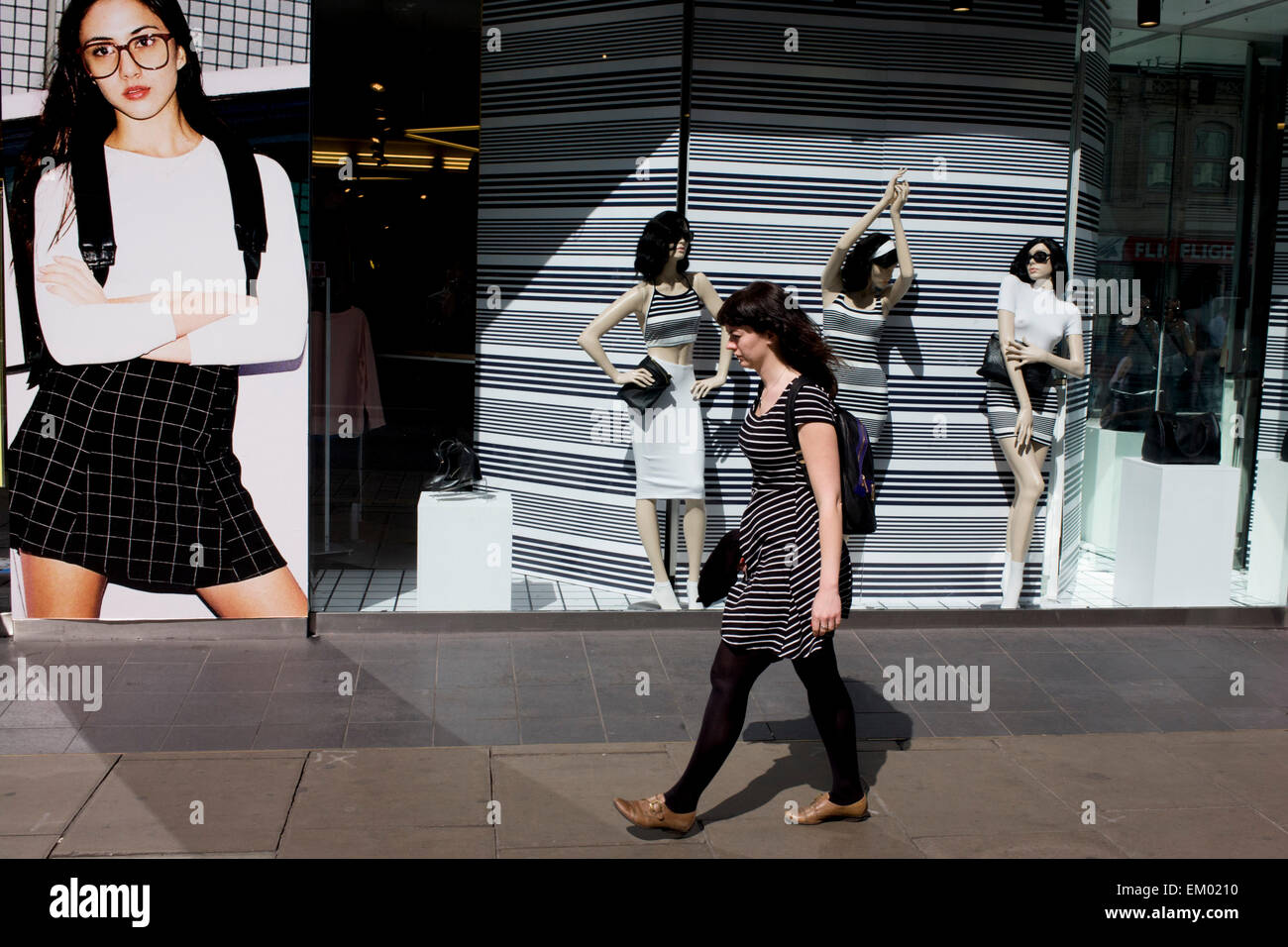 Woman shopper walks past stripe-themed shop window display Stock Photo ...