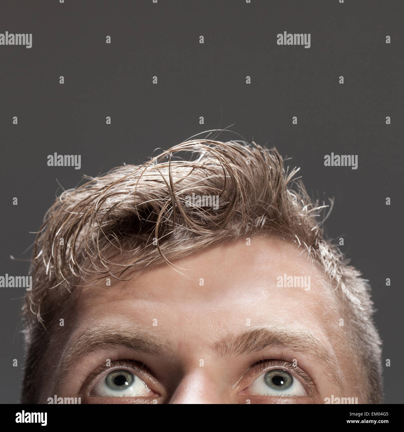 Young man looking up over grey background Stock Photo - Alamy