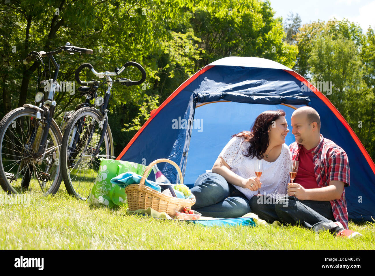 Happy couple on a camping drinking prosecco Stock Photo - Alamy