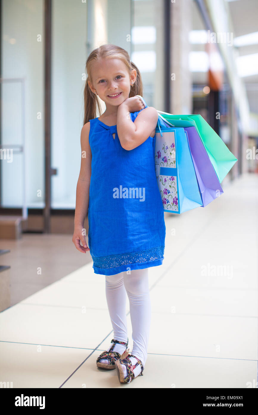 Little fashion girl with packages in large shopping center Stock Photo ...