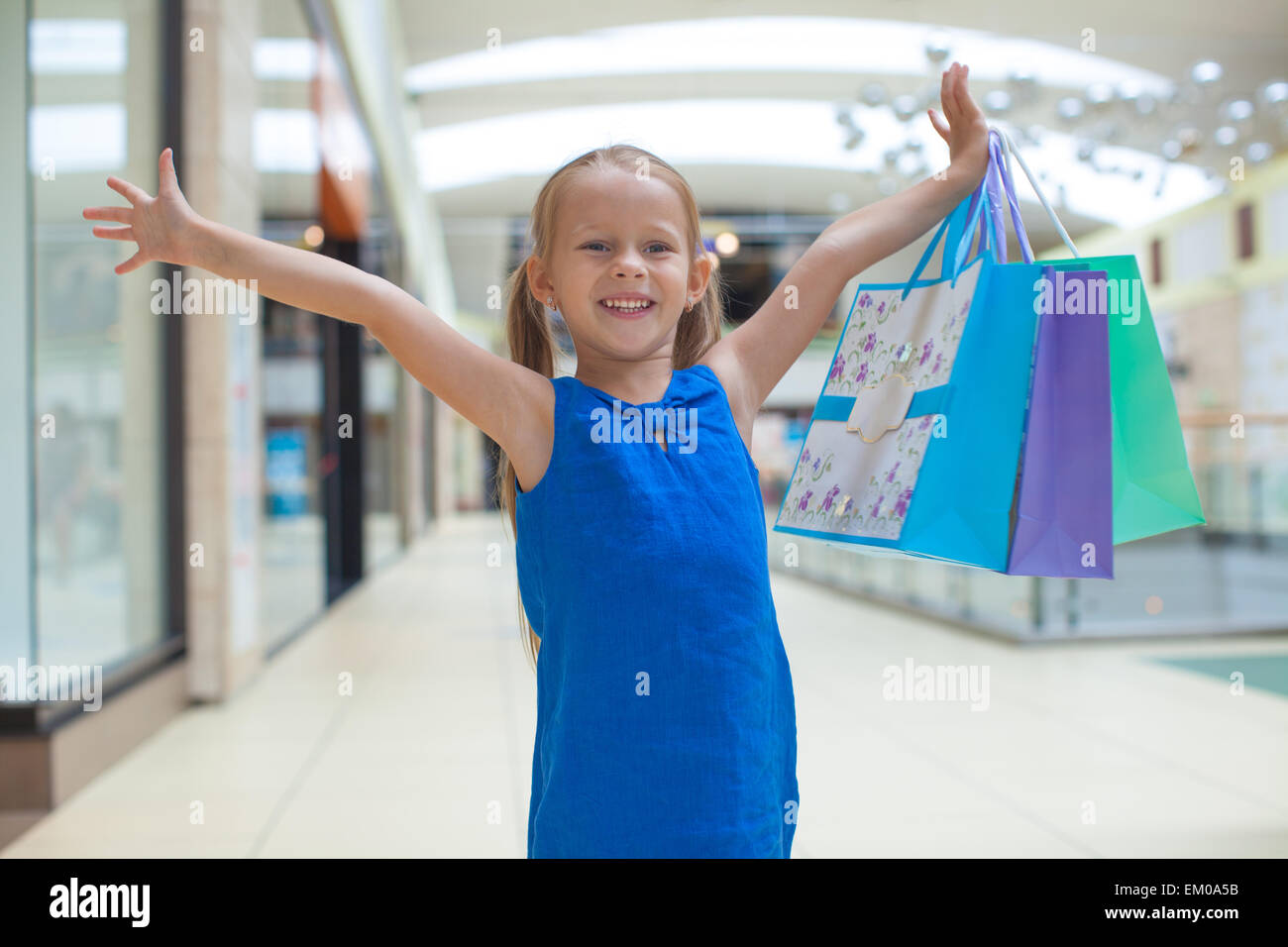 Little happy girl with packages in a large shopping center Stock Photo ...