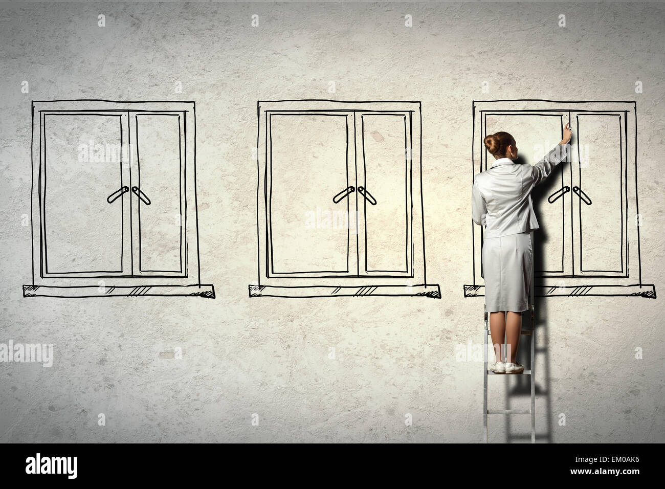 Woman standing on ladder drawing on wall Stock Photo - Alamy