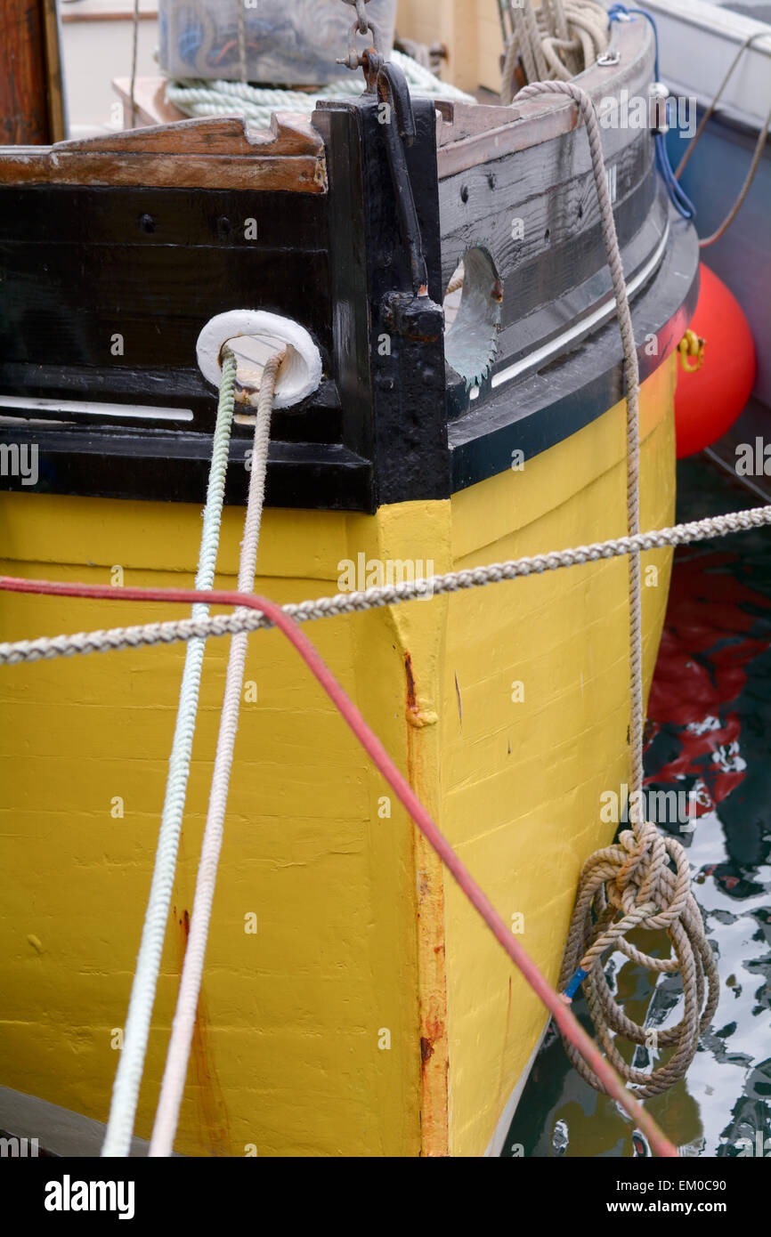Hull and bow of moored trawler boat painted bright yellow in Looe ...