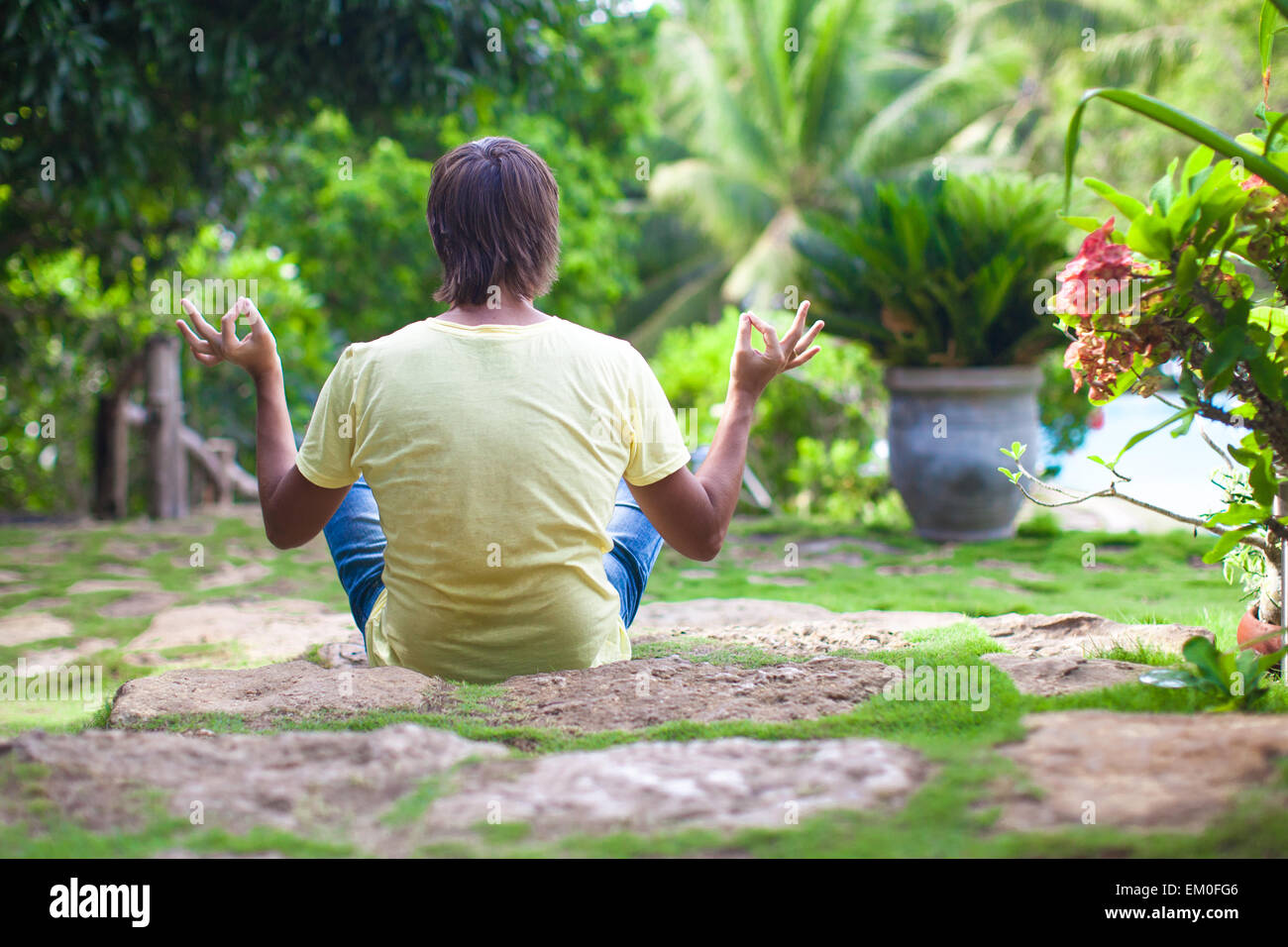 Young man sitting in the lotus position in the garden in beautiful ...