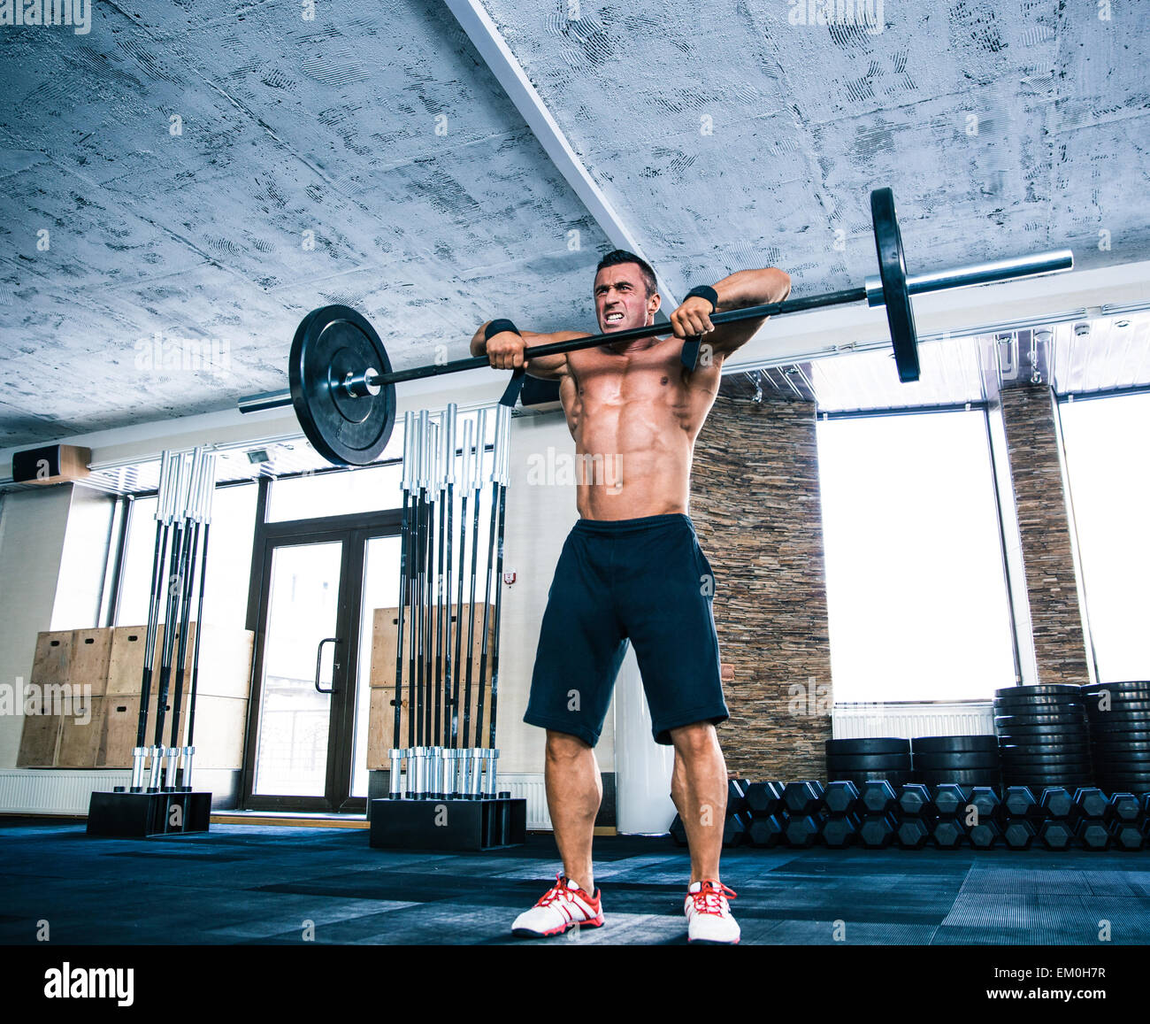 Muscular man lifting barbell at gym Stock Photo - Alamy