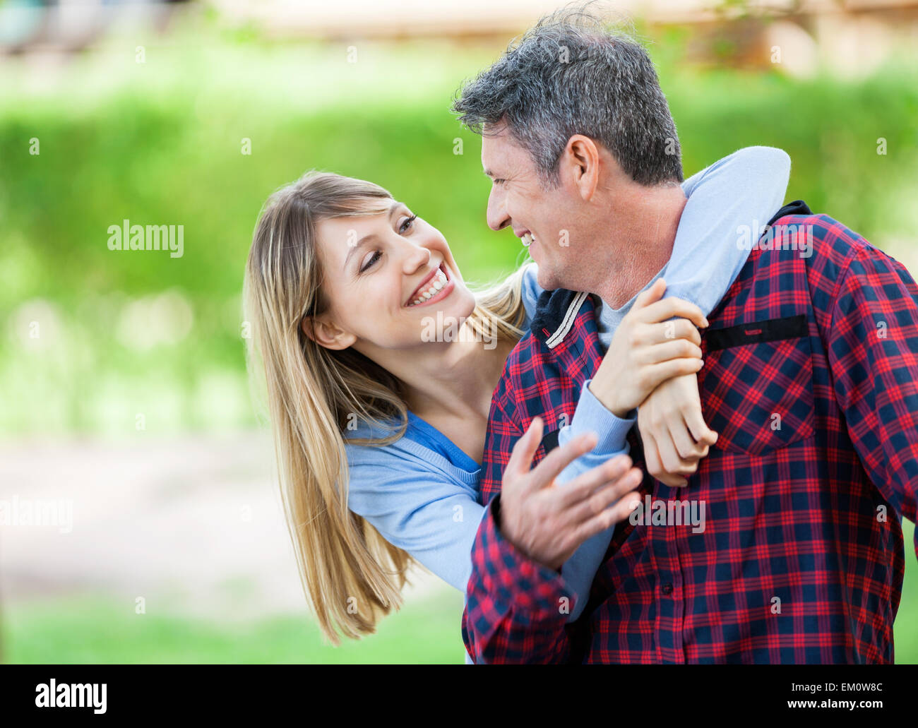 Woman Embracing Boyfriend In Park Stock Photo - Alamy