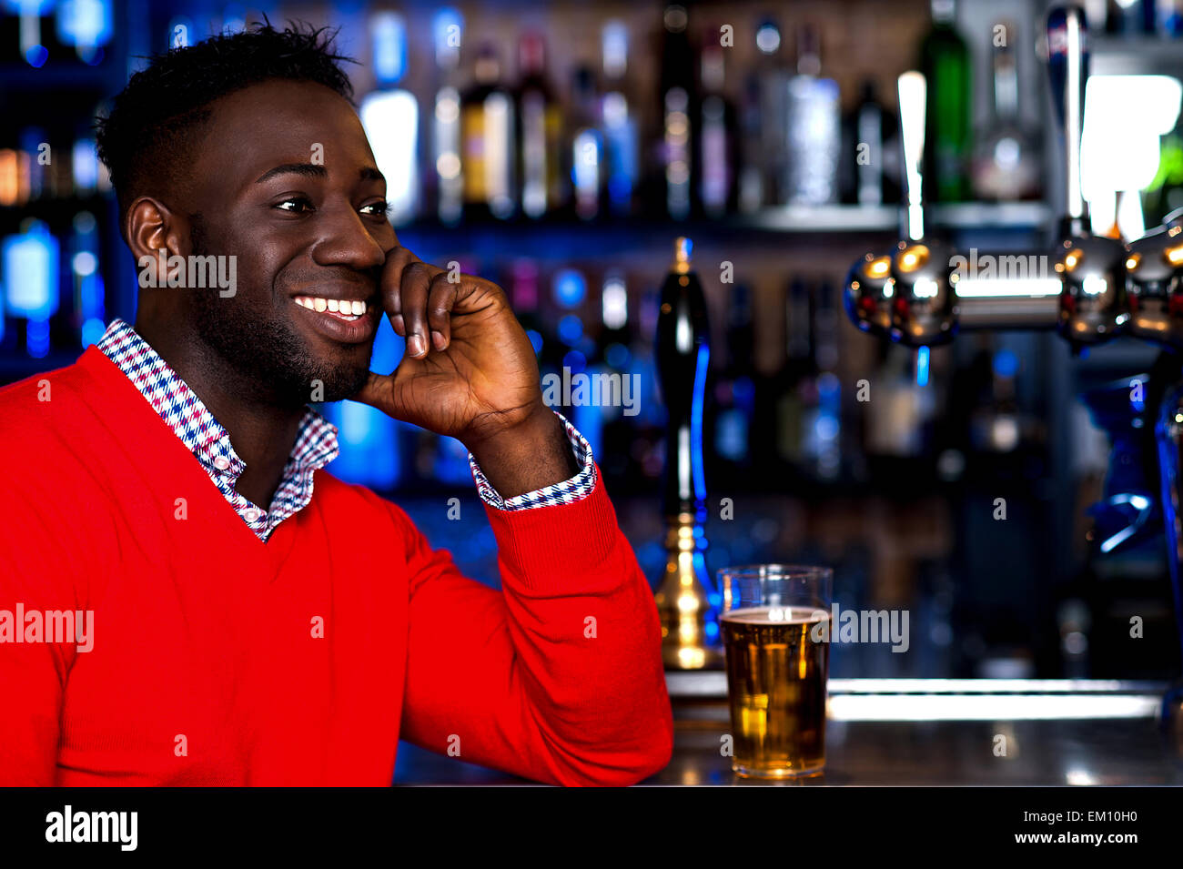 Smiling young guy in bar looking at something Stock Photo - Alamy
