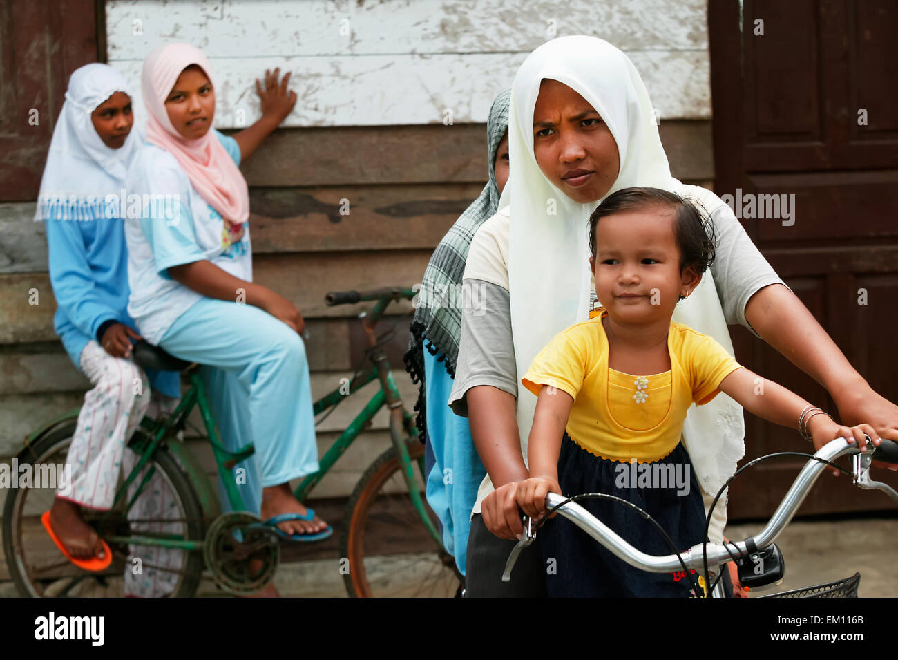 Muslim girls in headscarves play on bicycles; Banda Aceh, Aceh Province ...