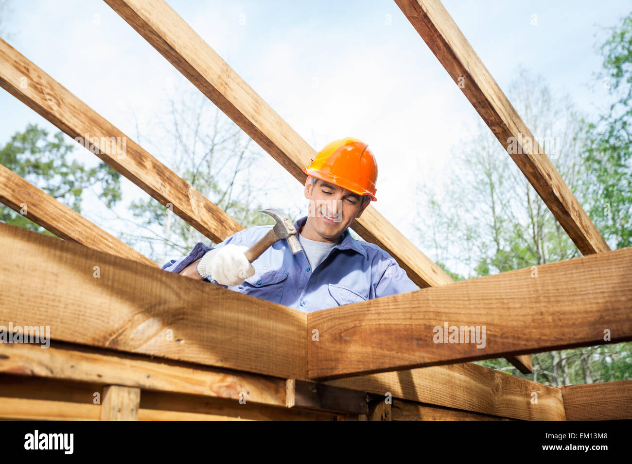 Worker Hammering Nail On Incomplete Timber Cabin At Site Stock Photo ...