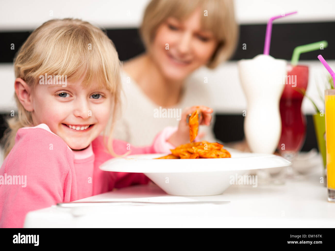 Cute kid enjoying pasta and juice Stock Photo - Alamy
