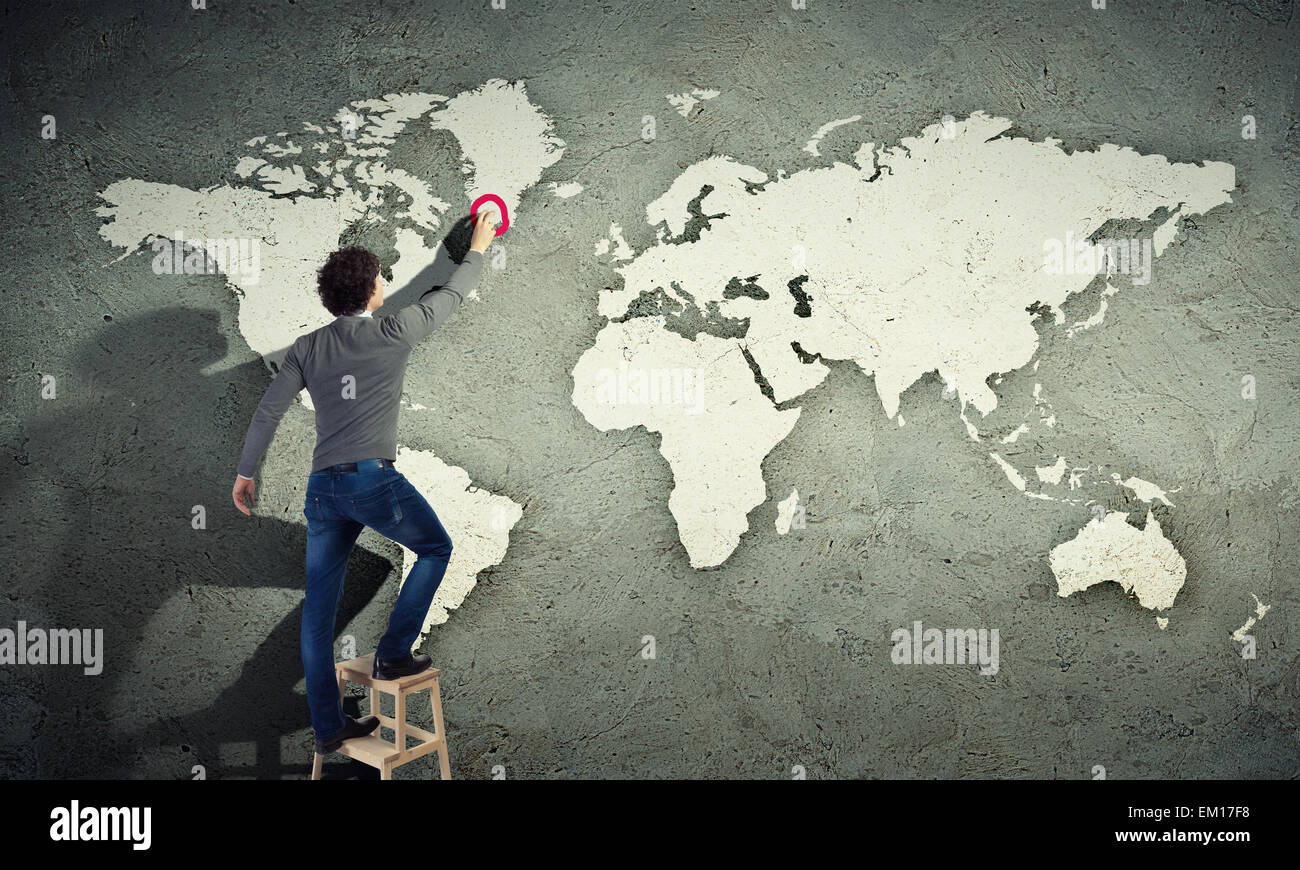 Young man drawing a map on the wall Stock Photo - Alamy