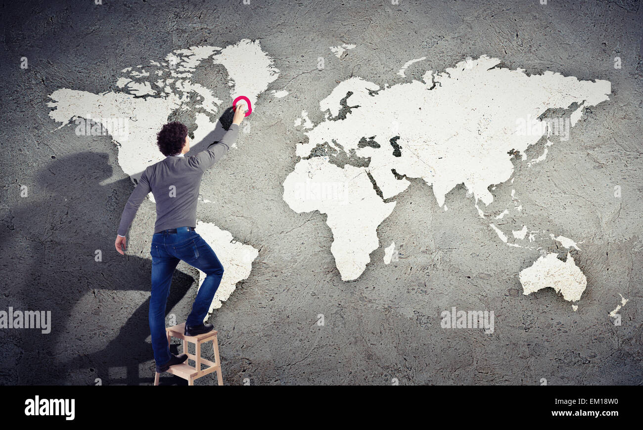 Young man drawing a map on the wall Stock Photo - Alamy