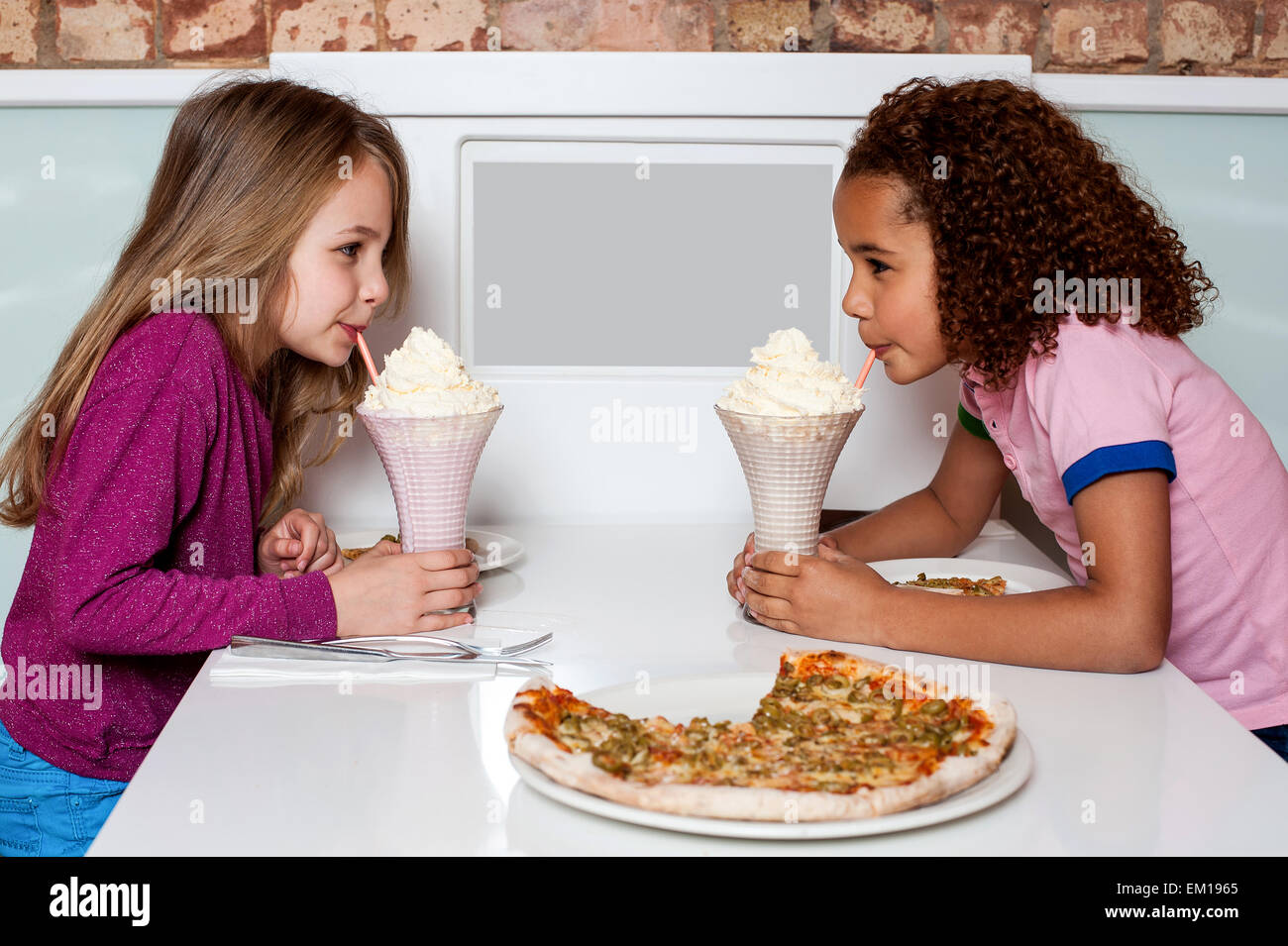 Young girls sipping strawberry shake Stock Photo - Alamy