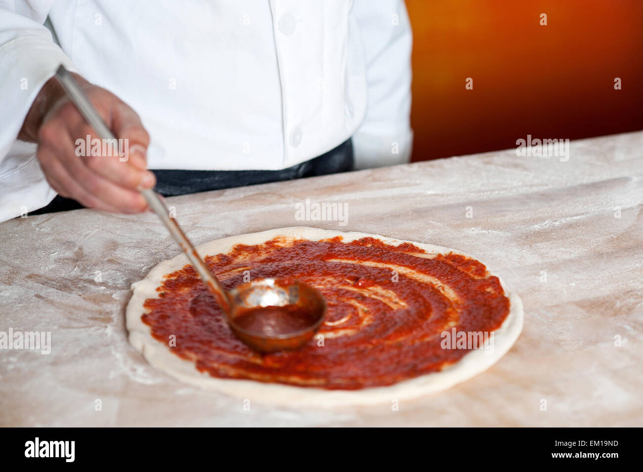 Chef baker spreading sauce on pizza base Stock Photo - Alamy