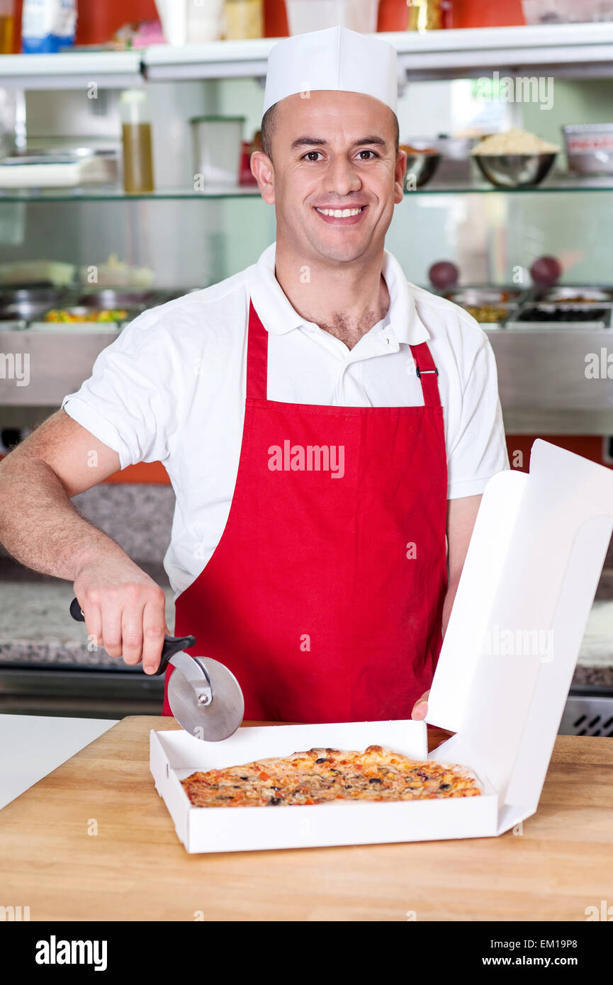 Chef holding pizza cuter, ready to cut Stock Photo - Alamy