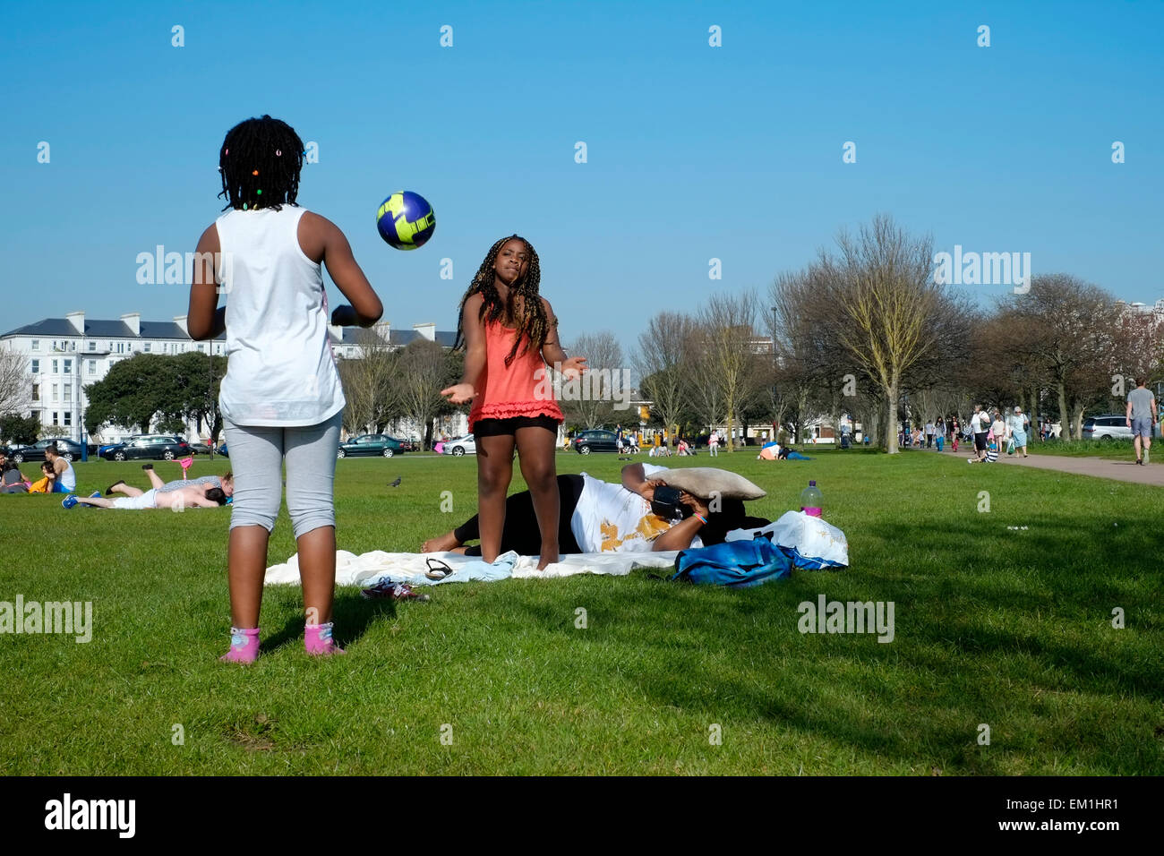 two young girls playing catch with a ball on a glorious sunny afternoon ...