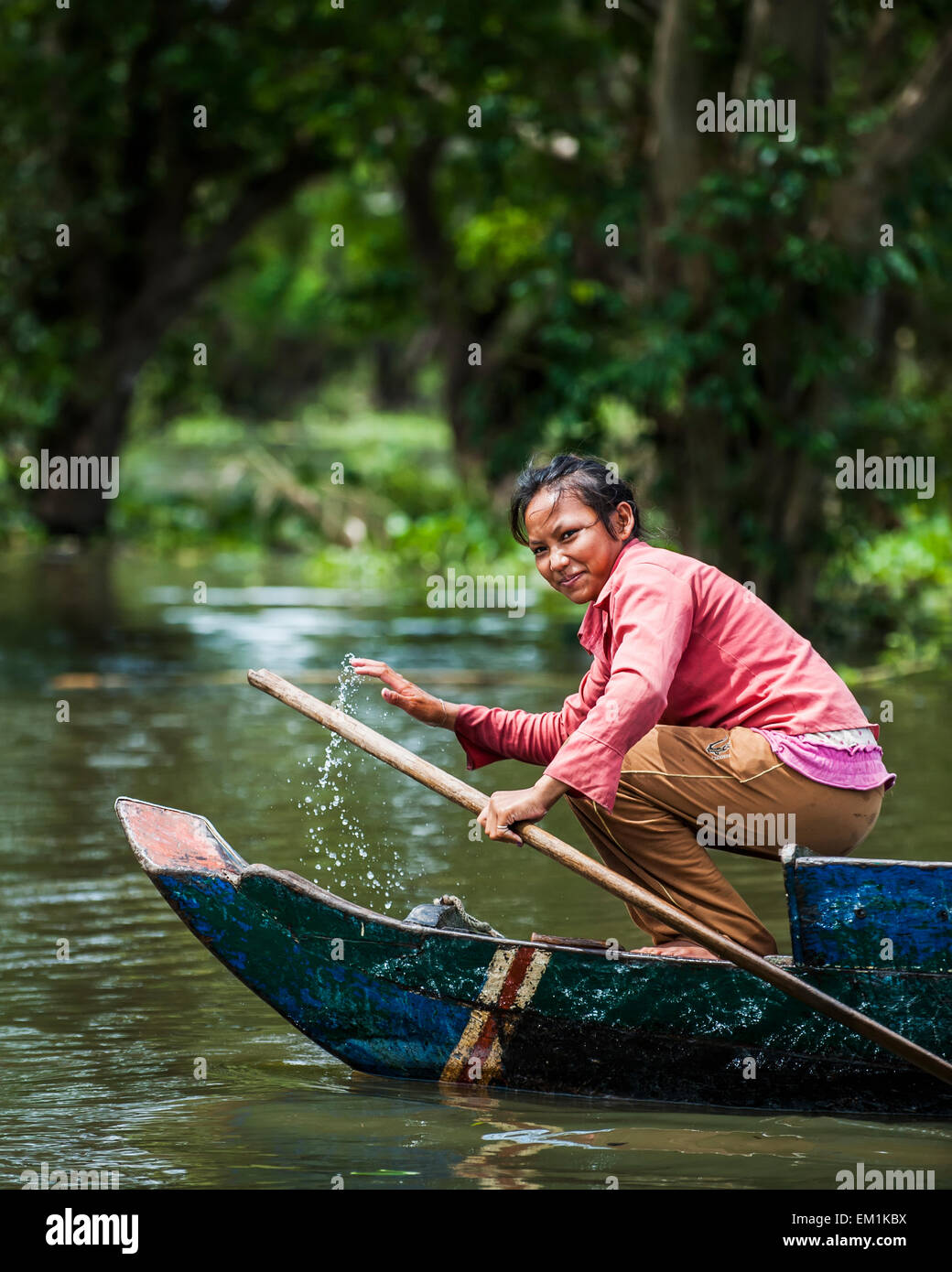 Water dripping off a woman's hand as she crouches at the bow of a boat ...
