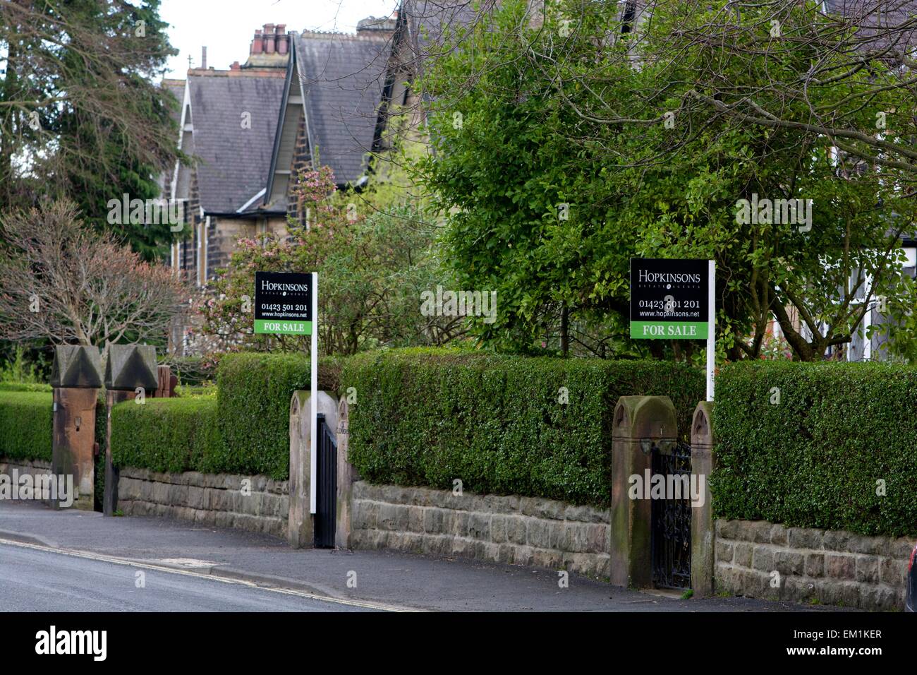 two estate agents' "for sale" signs in the gardens of adjoining houses ...