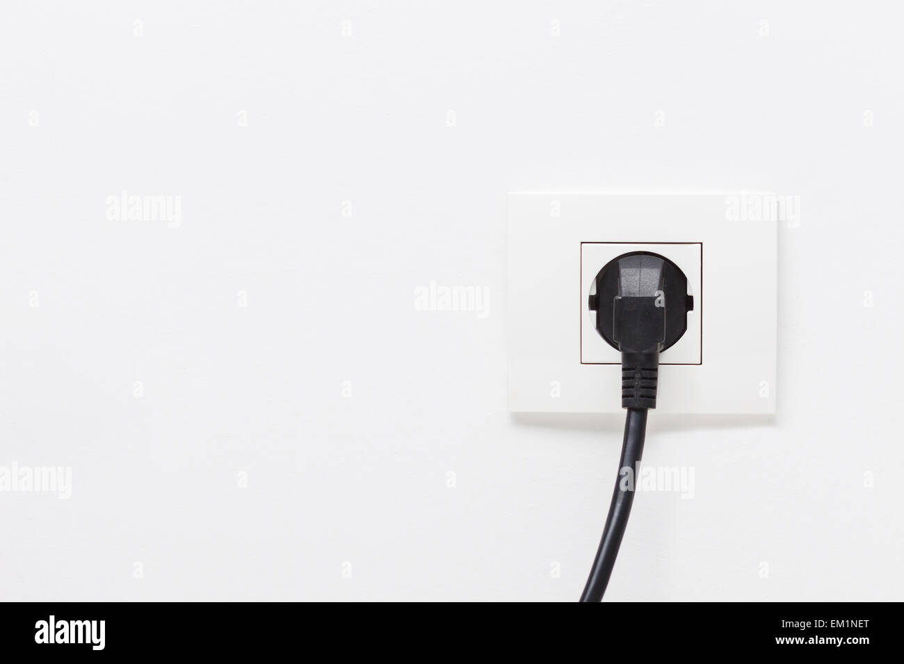 Black electric cord plugged into a single electric socket on white ...