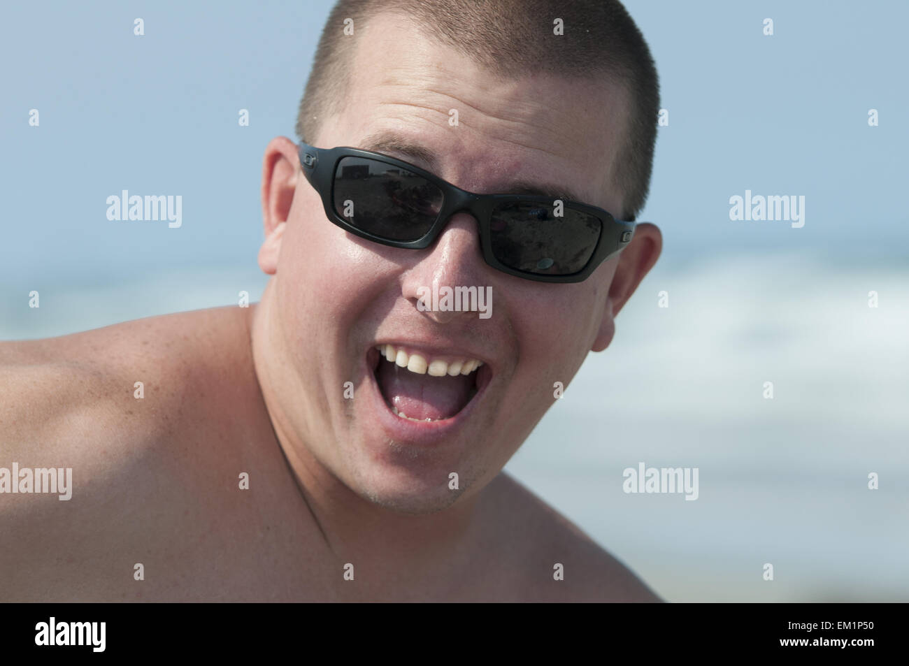 man on the beach. Image is close-up of his head. He is laughing and ...