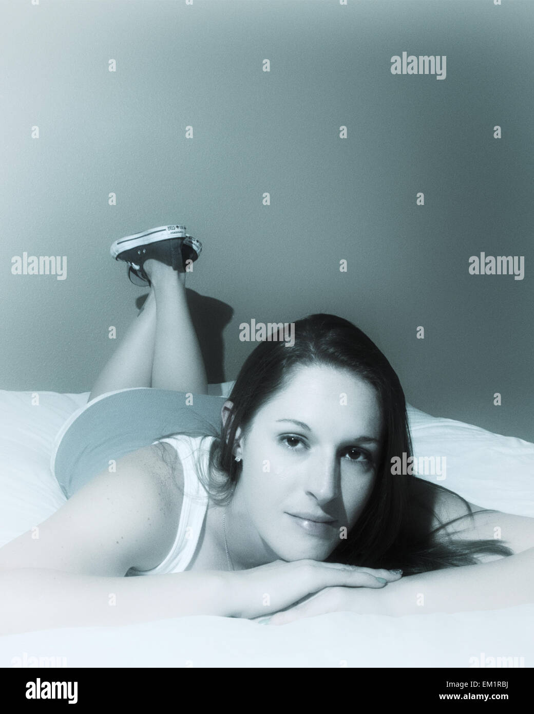 Woman Lying On Her Stomach On A Bed Her Feed Are Up And Crossed The