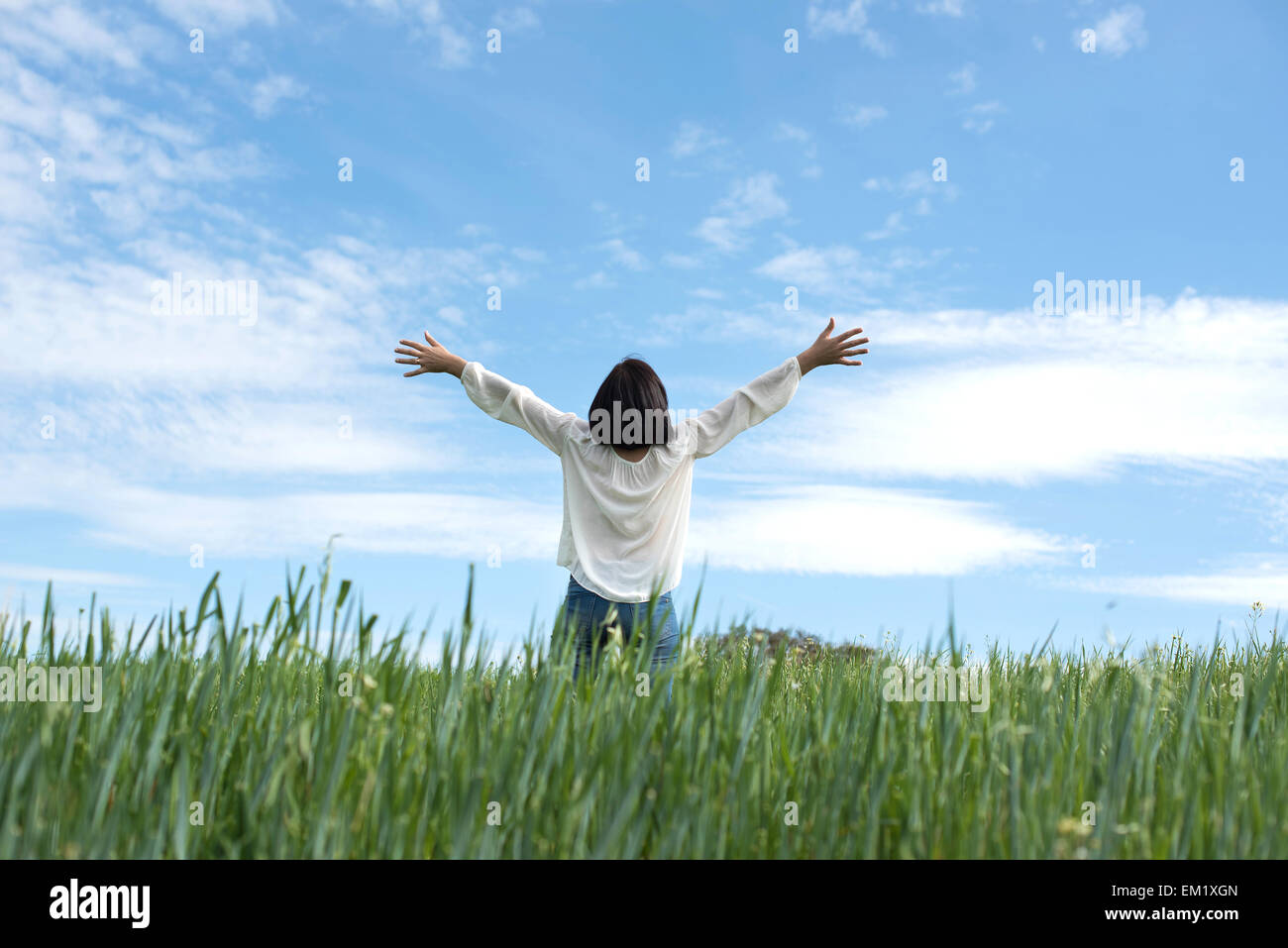 Woman with open arms in green field Stock Photo - Alamy