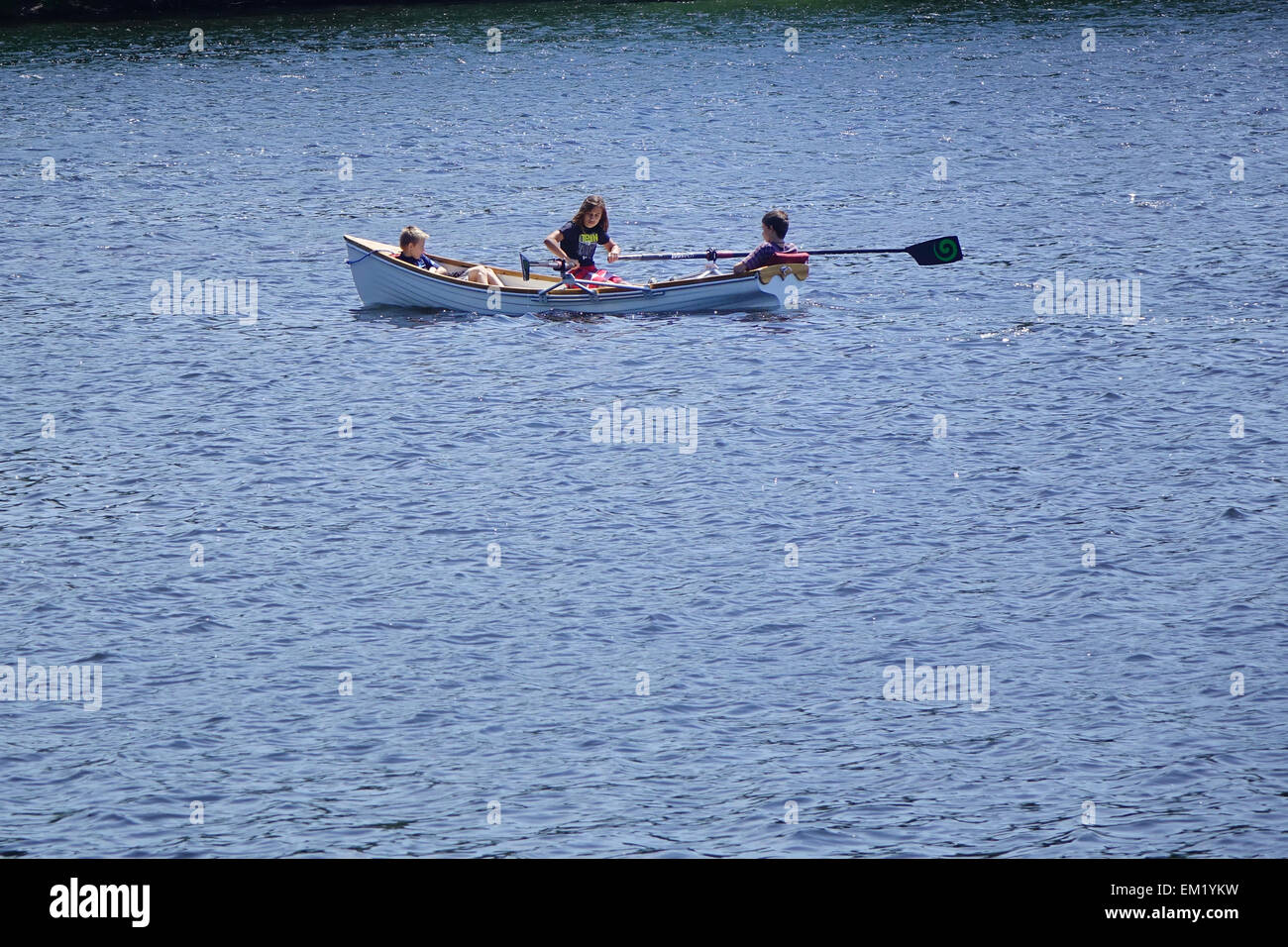 Girl rowing boat with younger boys as passengers Stock Photo - Alamy