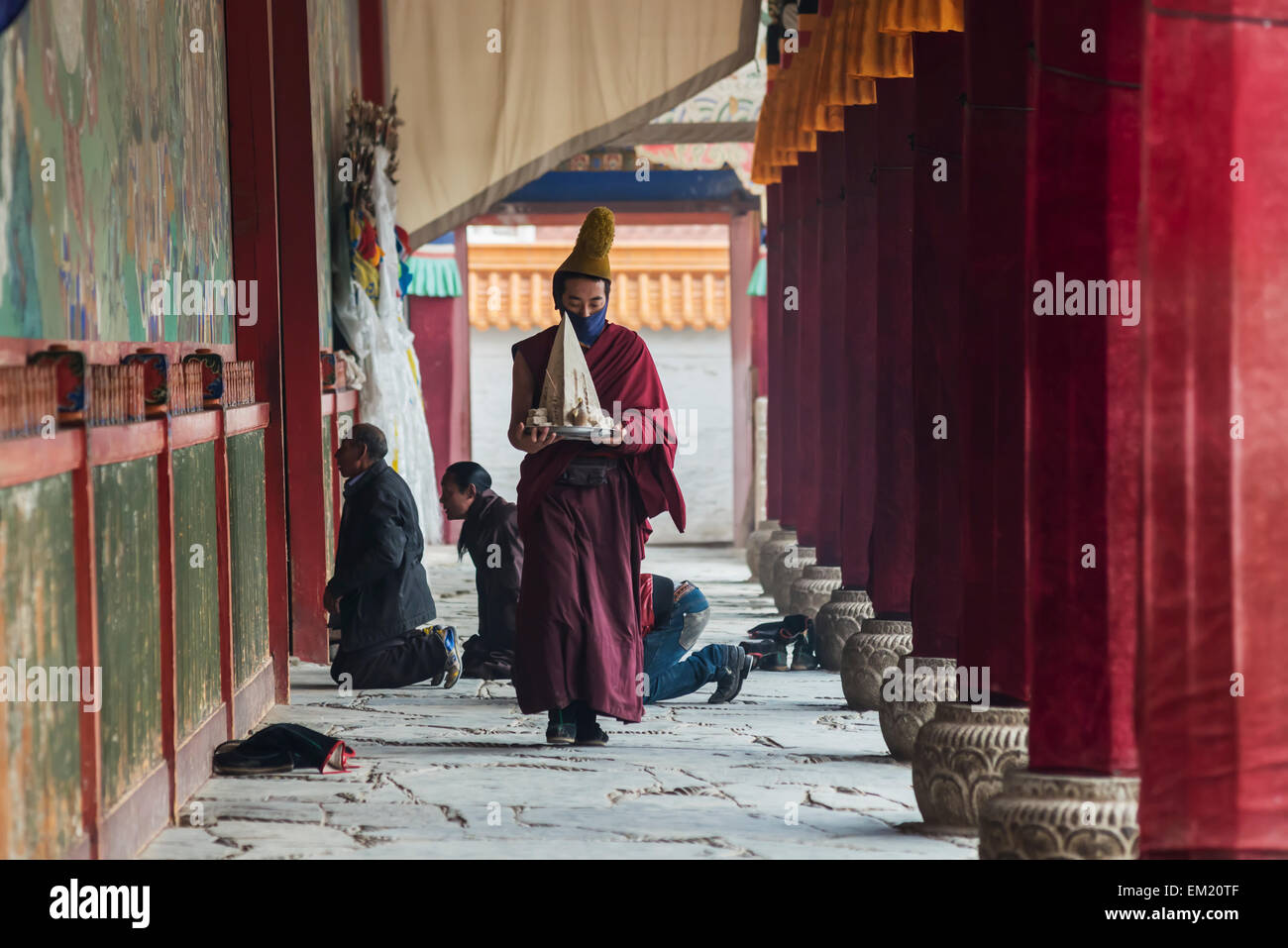A monk carrying an artifact of Buddhist praying ceremony at Labrang ...