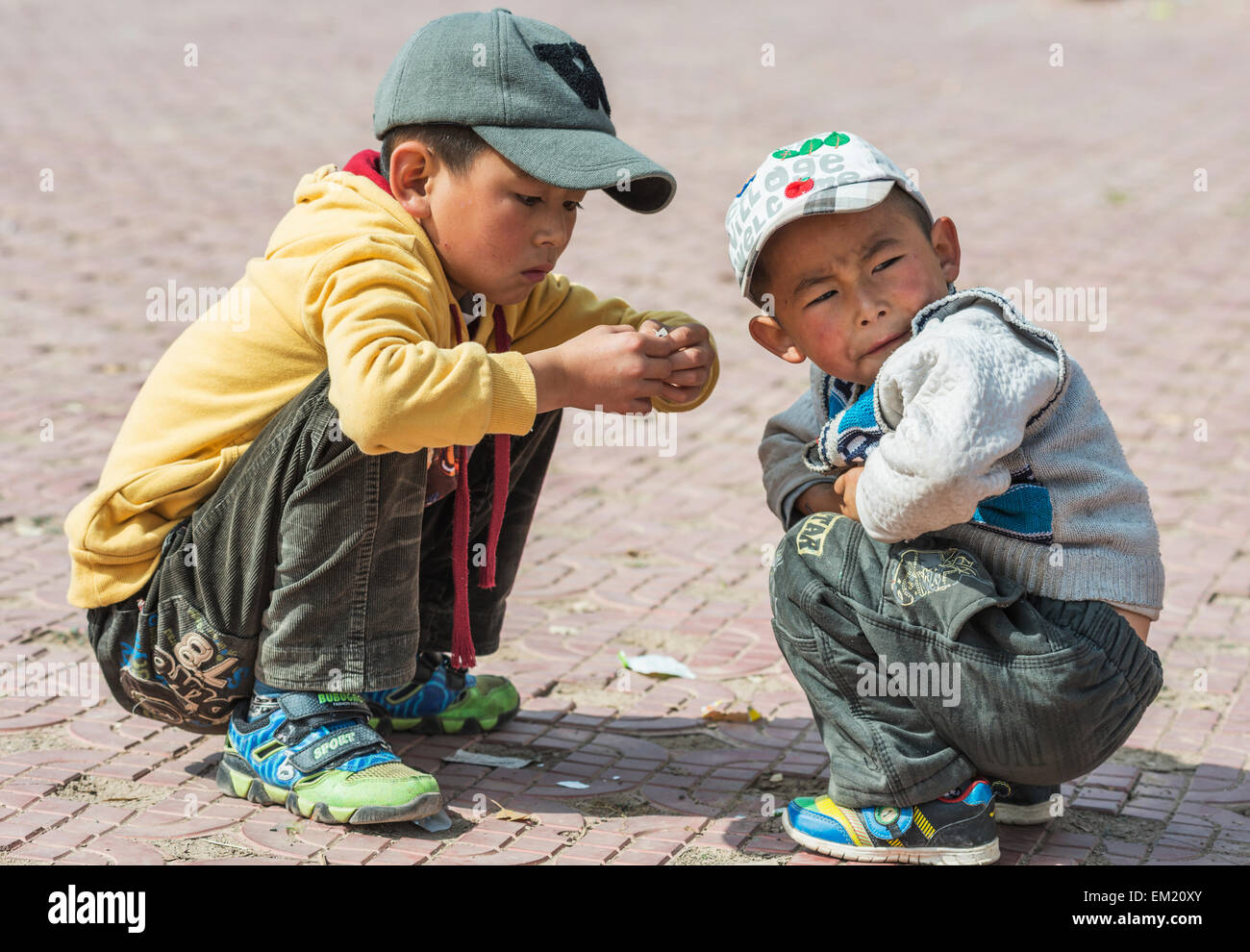 Tibetan children are playing near Buddhist Wutun Si monastery square ...