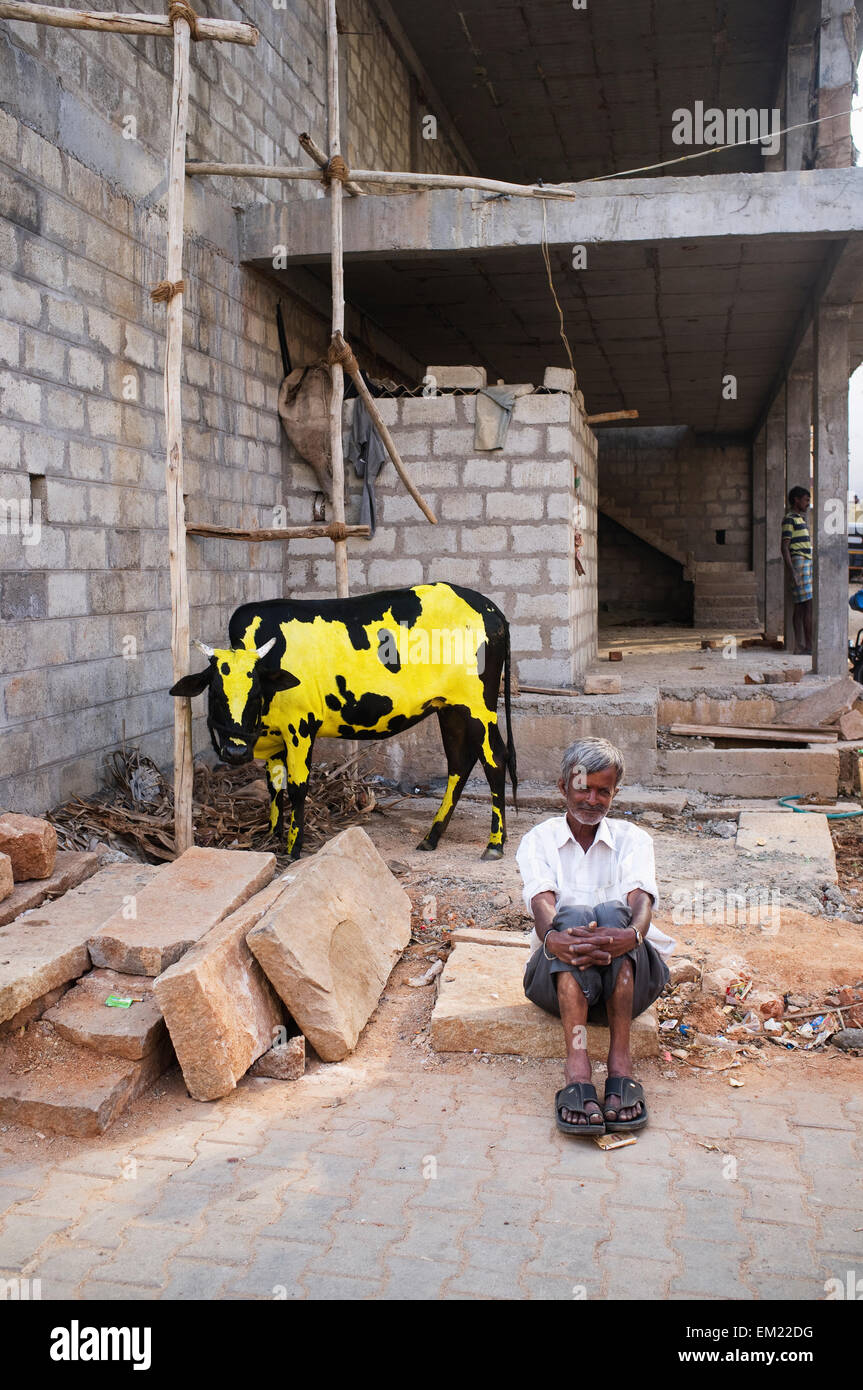 A man sits outside a building under construction with a painted yellow ...