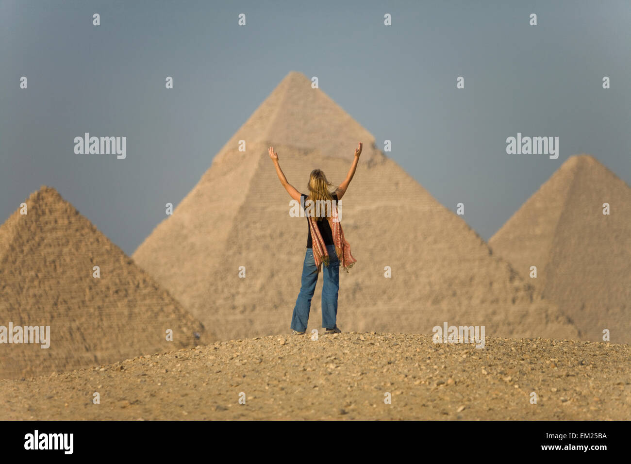 A Female Tourist Raises Her Arms And Looks Out Toward The Pyramids Of ...