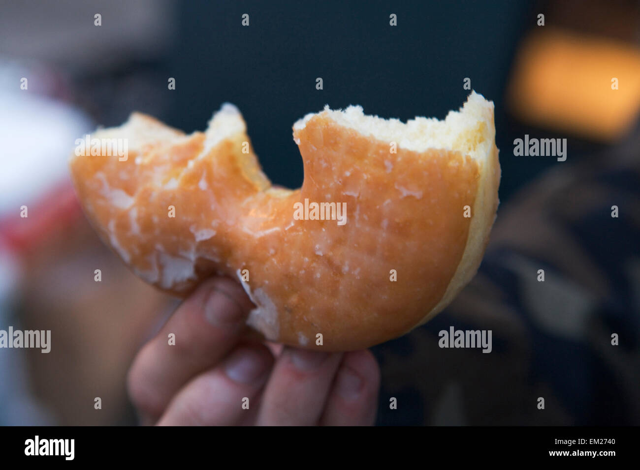 A hand holding a half eaten doughnut Stock Photo - Alamy