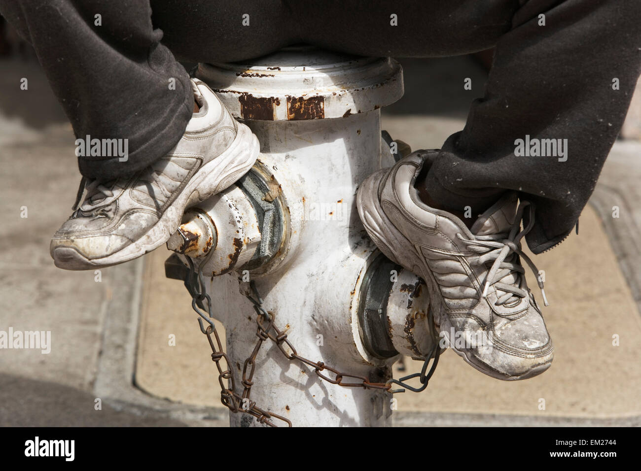 A person sitting on a fire hydrant Stock Photo - Alamy