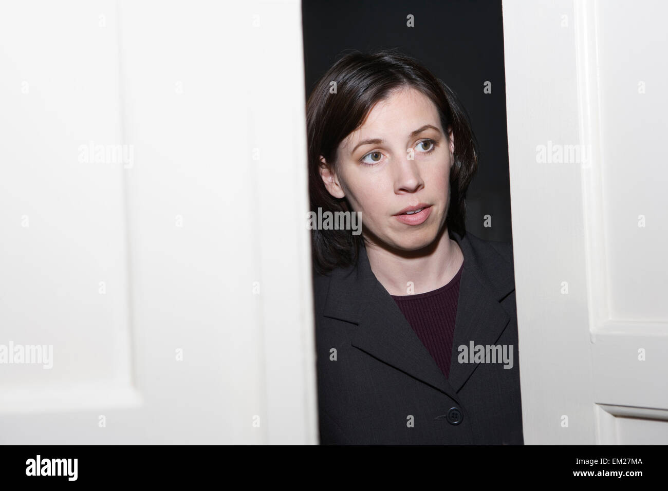 A young woman looking through a doorway Stock Photo - Alamy