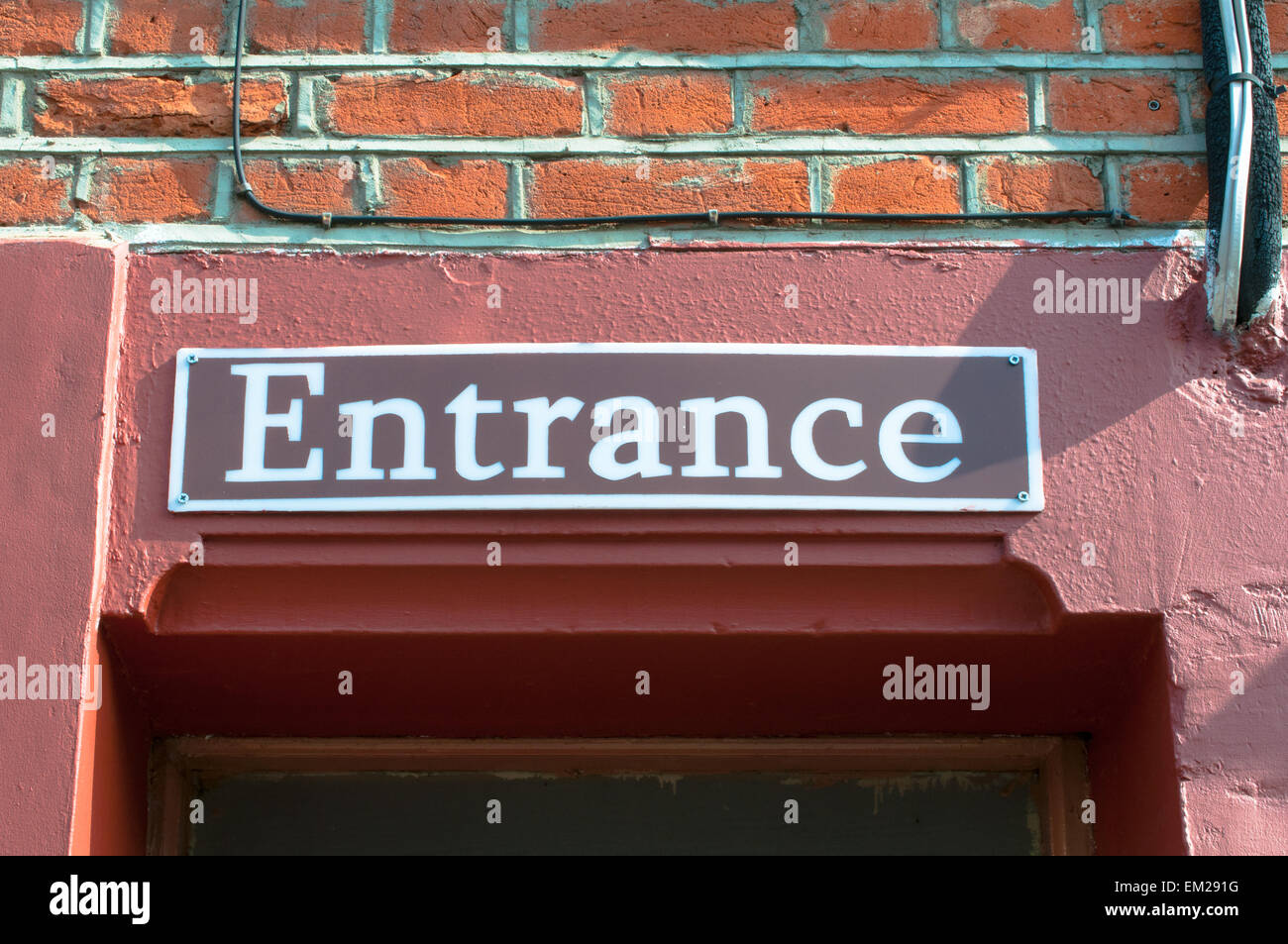 Entrance sign pasted on red bricked door Stock Photo - Alamy