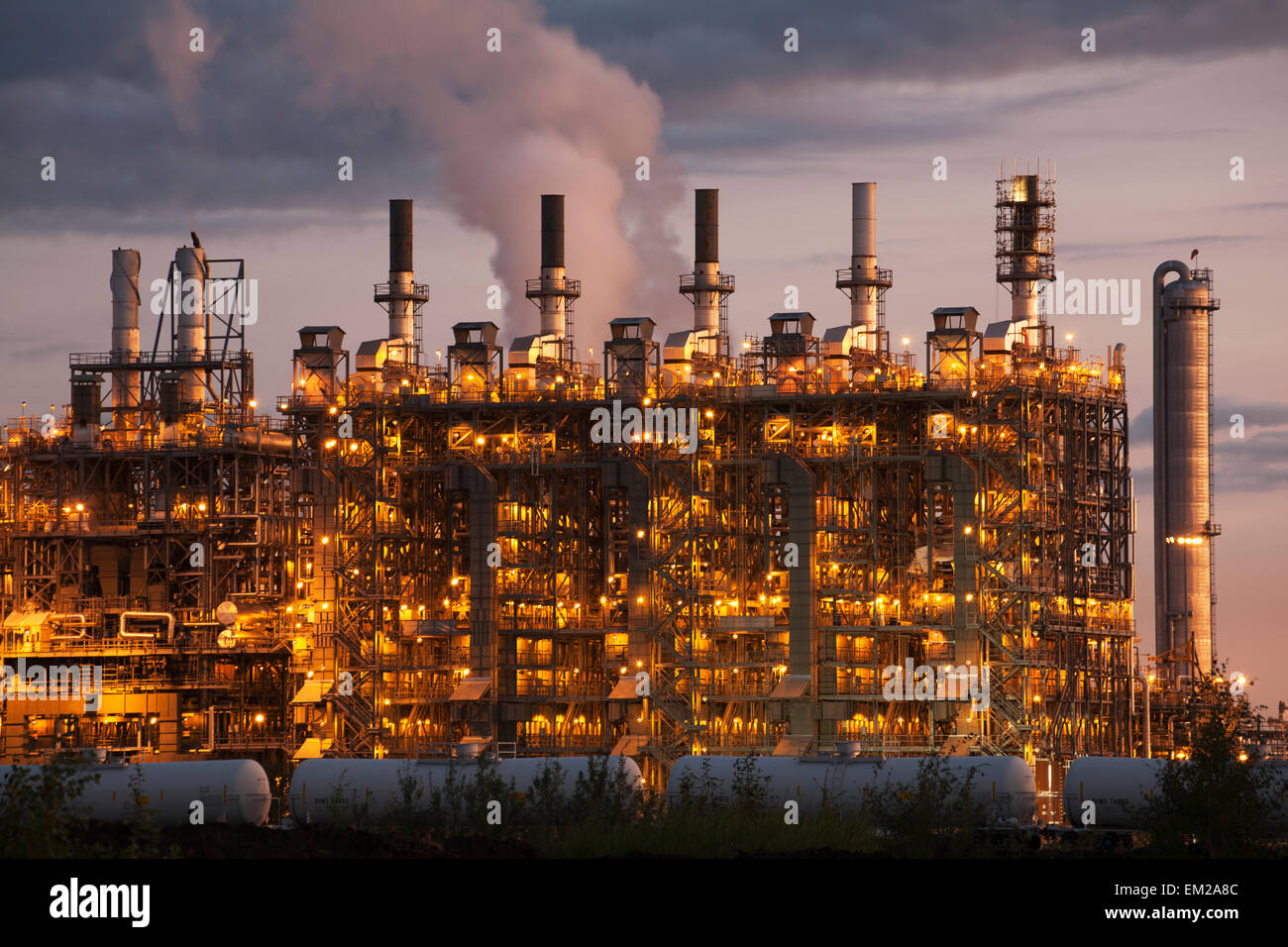 Towers Of A Refinery Illuminated By Lights At Dawn; Alberta Canada ...