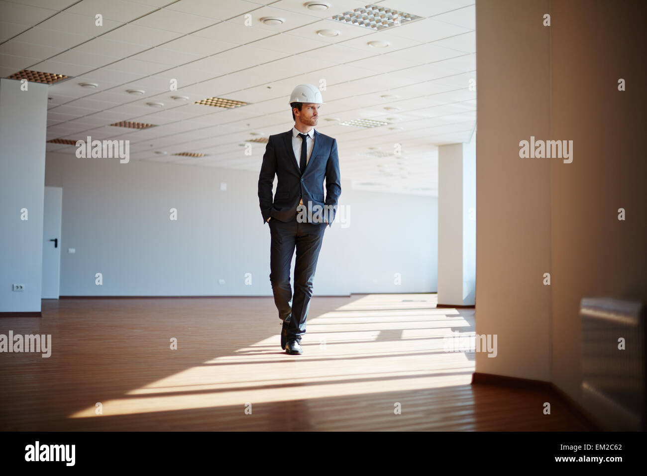 Male architect in suit and helmet walking along office Stock Photo - Alamy